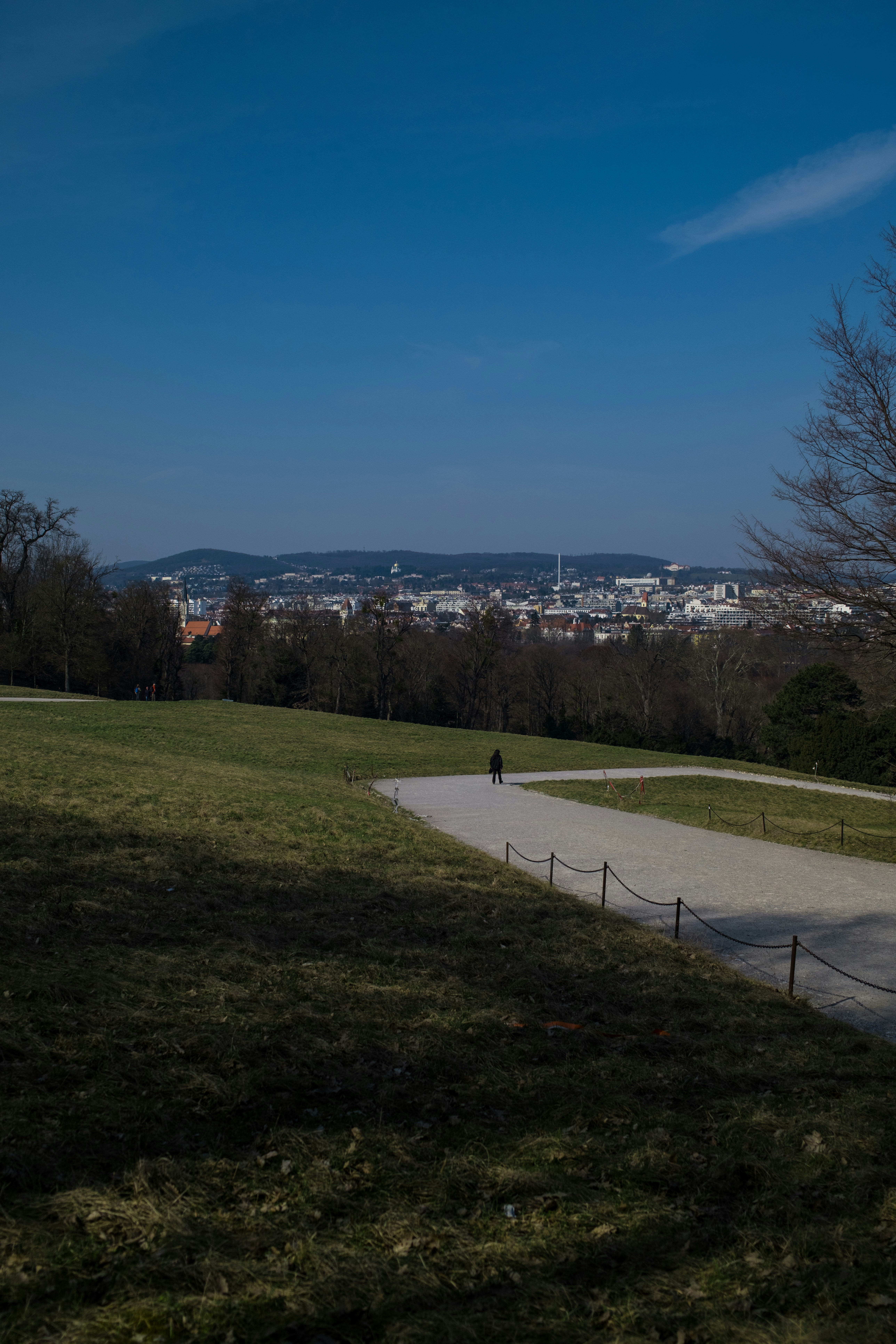 Hiker on a Sunlit Path Overlooking a Quiet Town