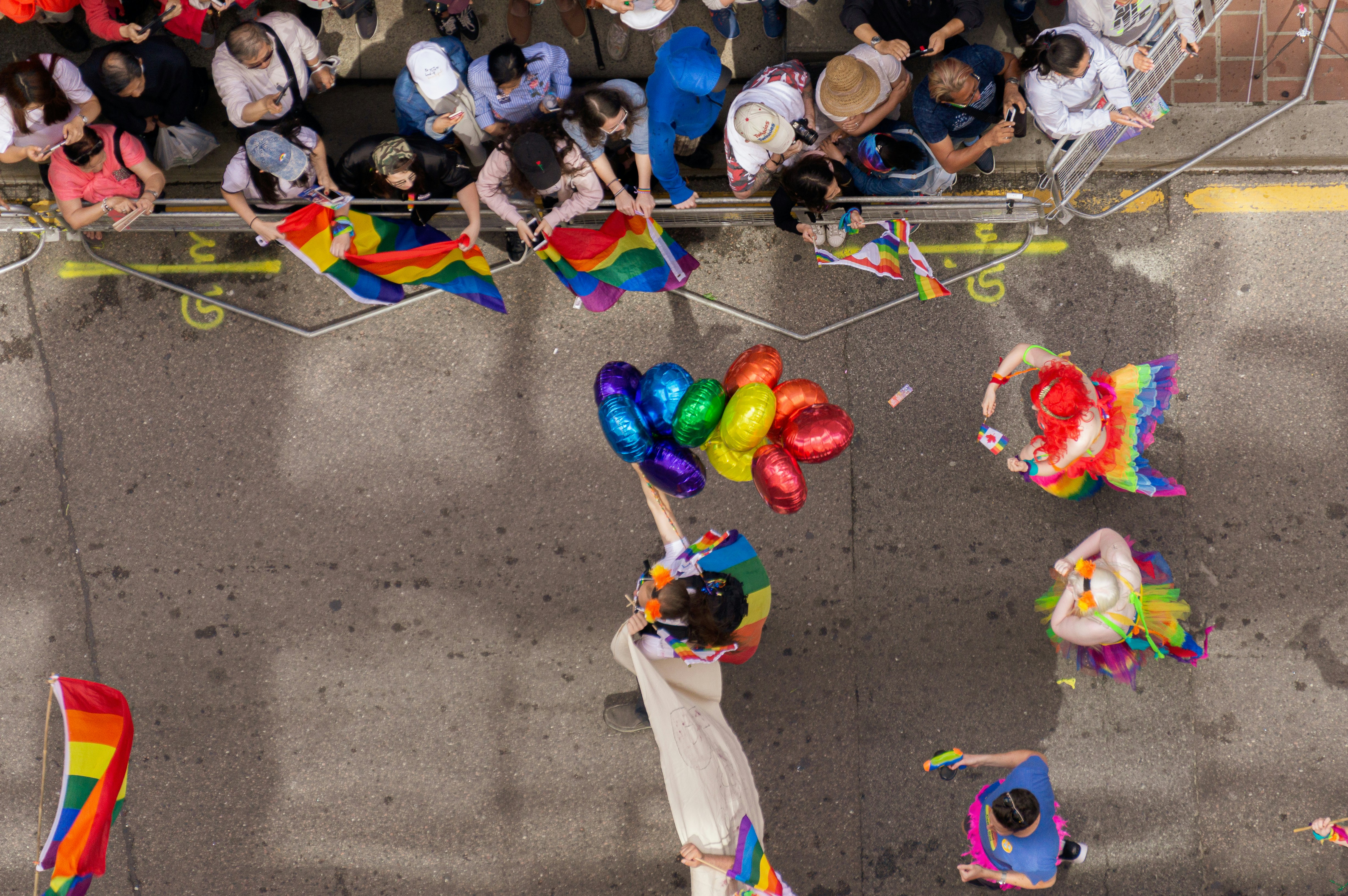 Rainbow Parade Aerial: Hands, Balloons, and Pride Flags Along the Street