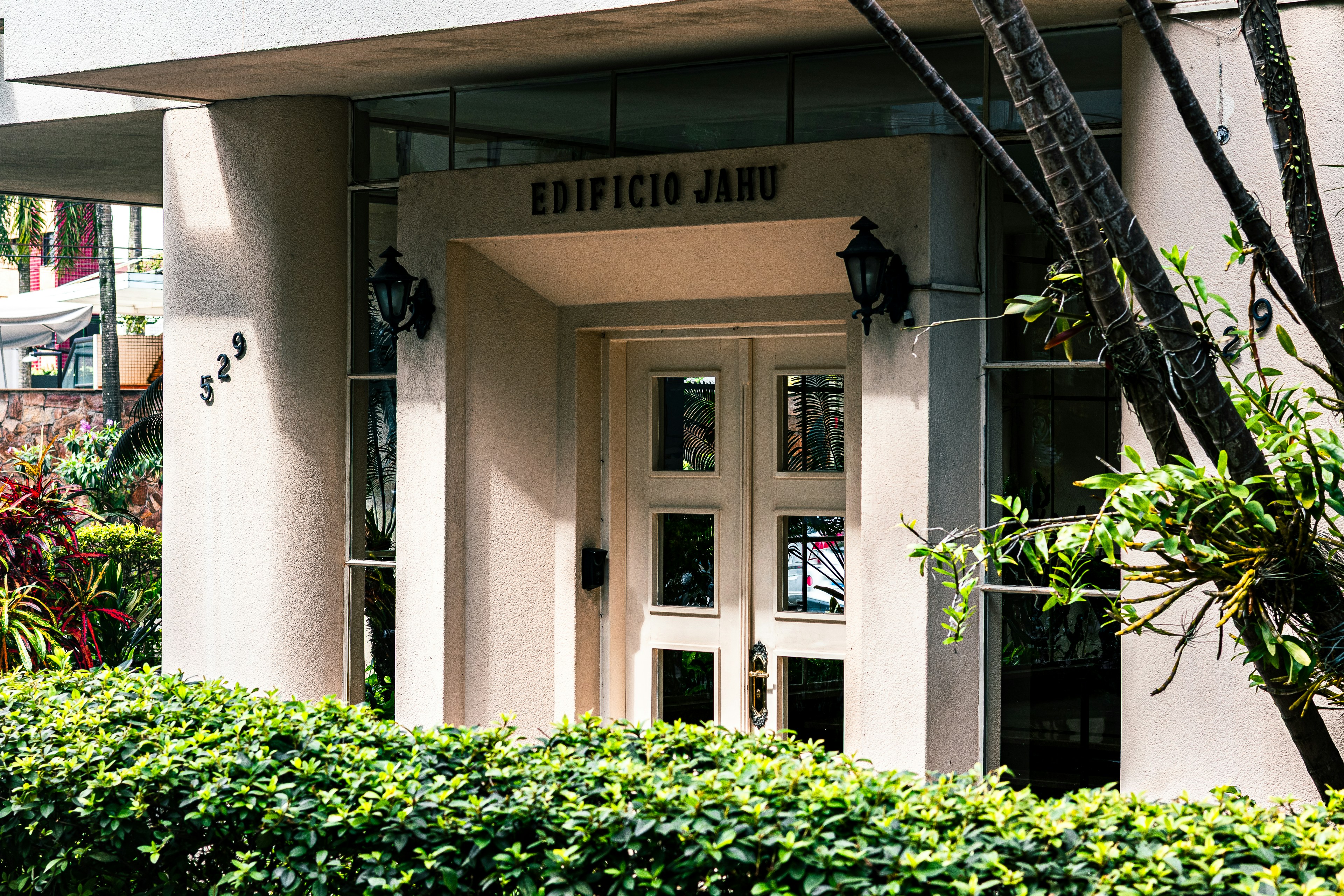 Edificio Jahu: A Quiet Entrance Through Shaded Foliage
