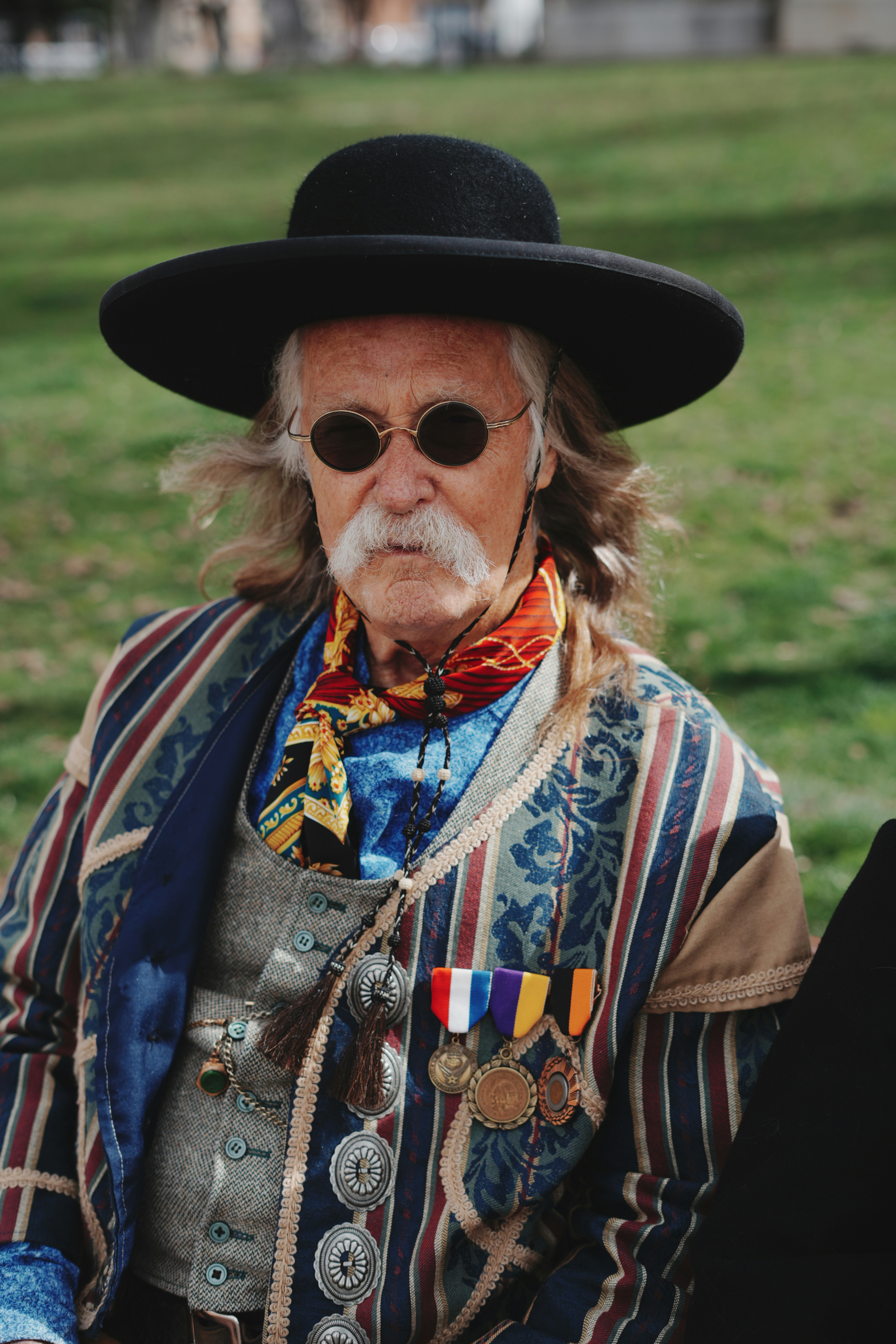 Vintage Gypsy Portrait: A Bold Hat, Round Glasses, and Colorful Medals