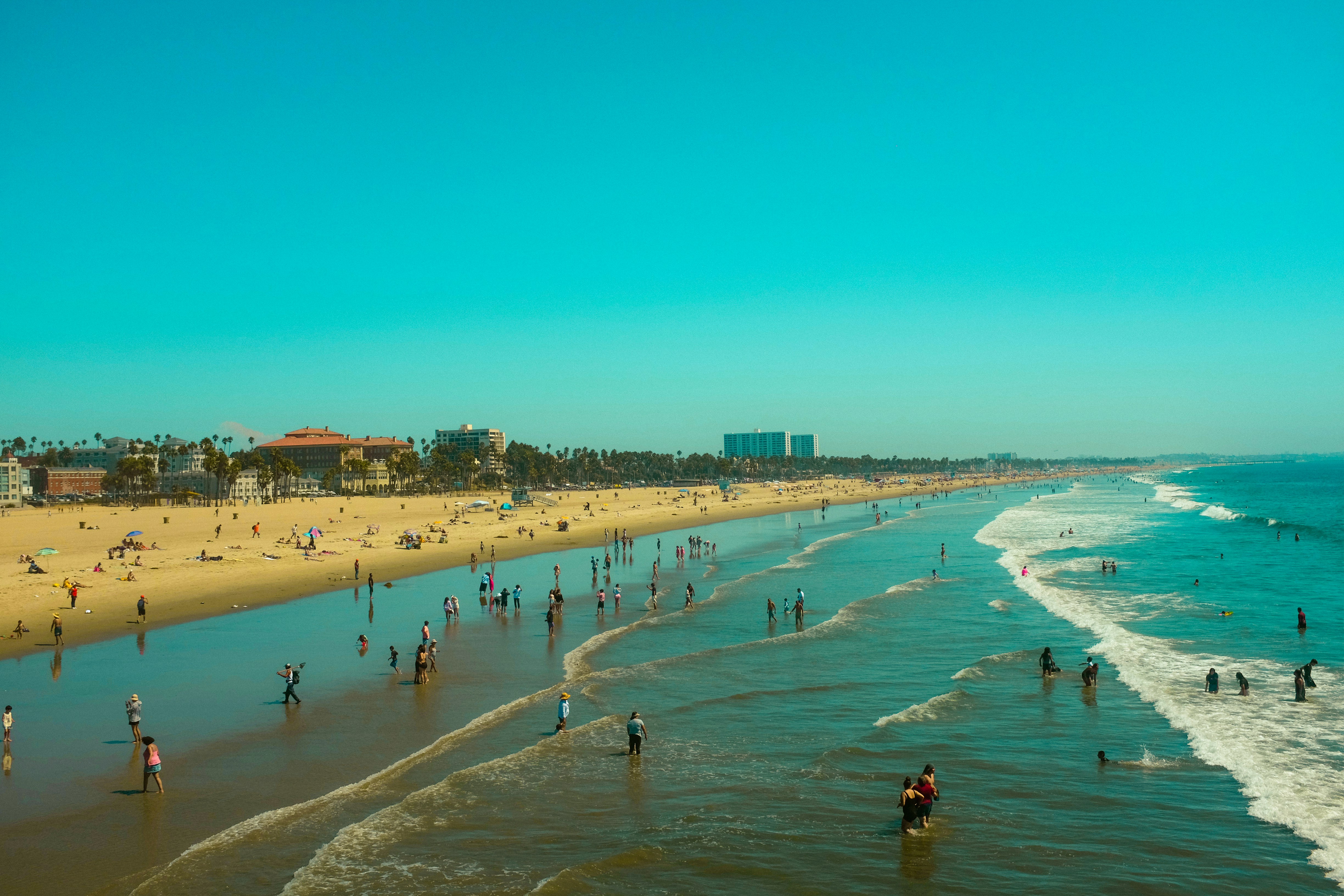 Sunlit Shoreline: Beachgoers Outline a Curving Golden Beach