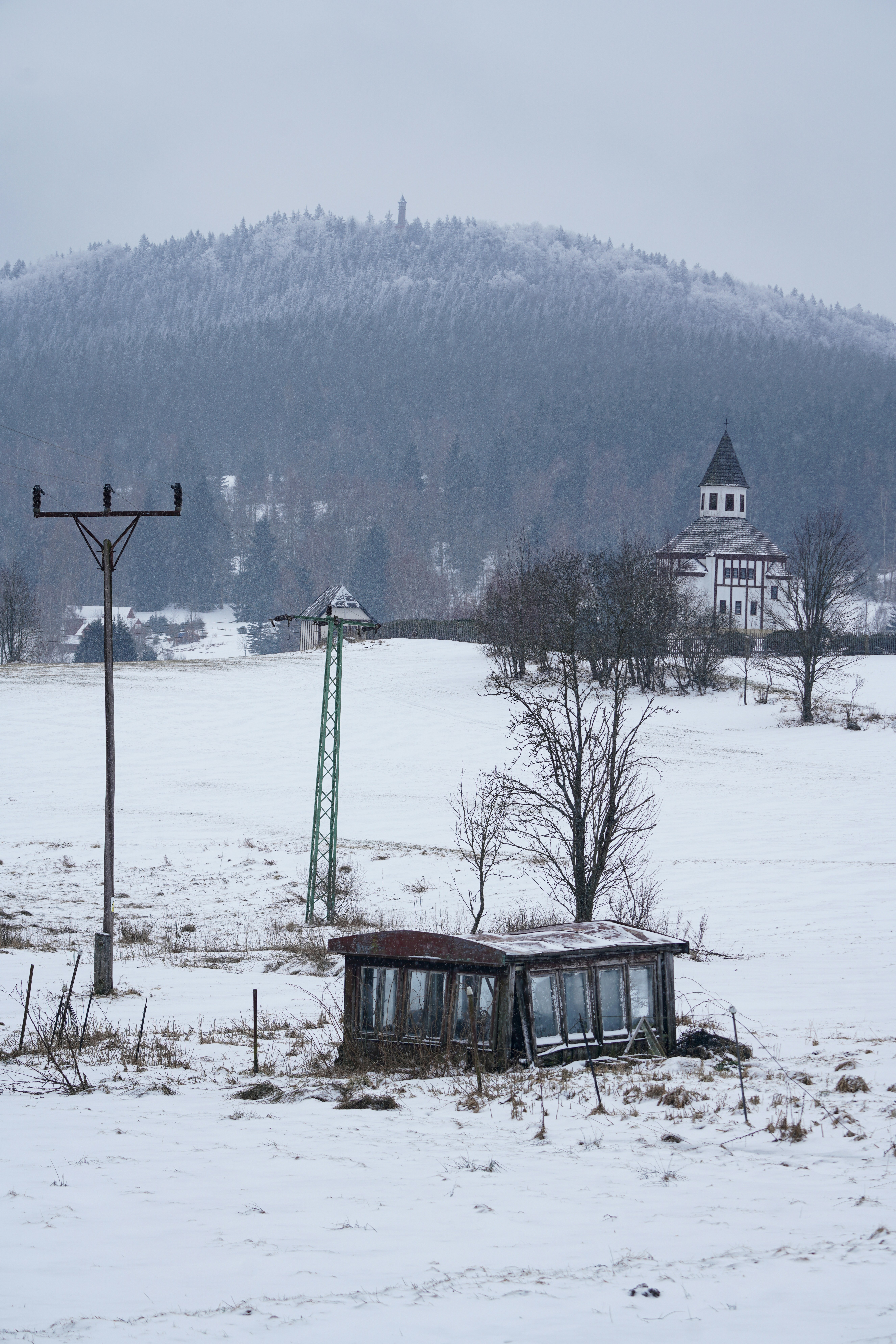 Wintry Silence: A Small Church Speckled by Snow against a Frozen Field