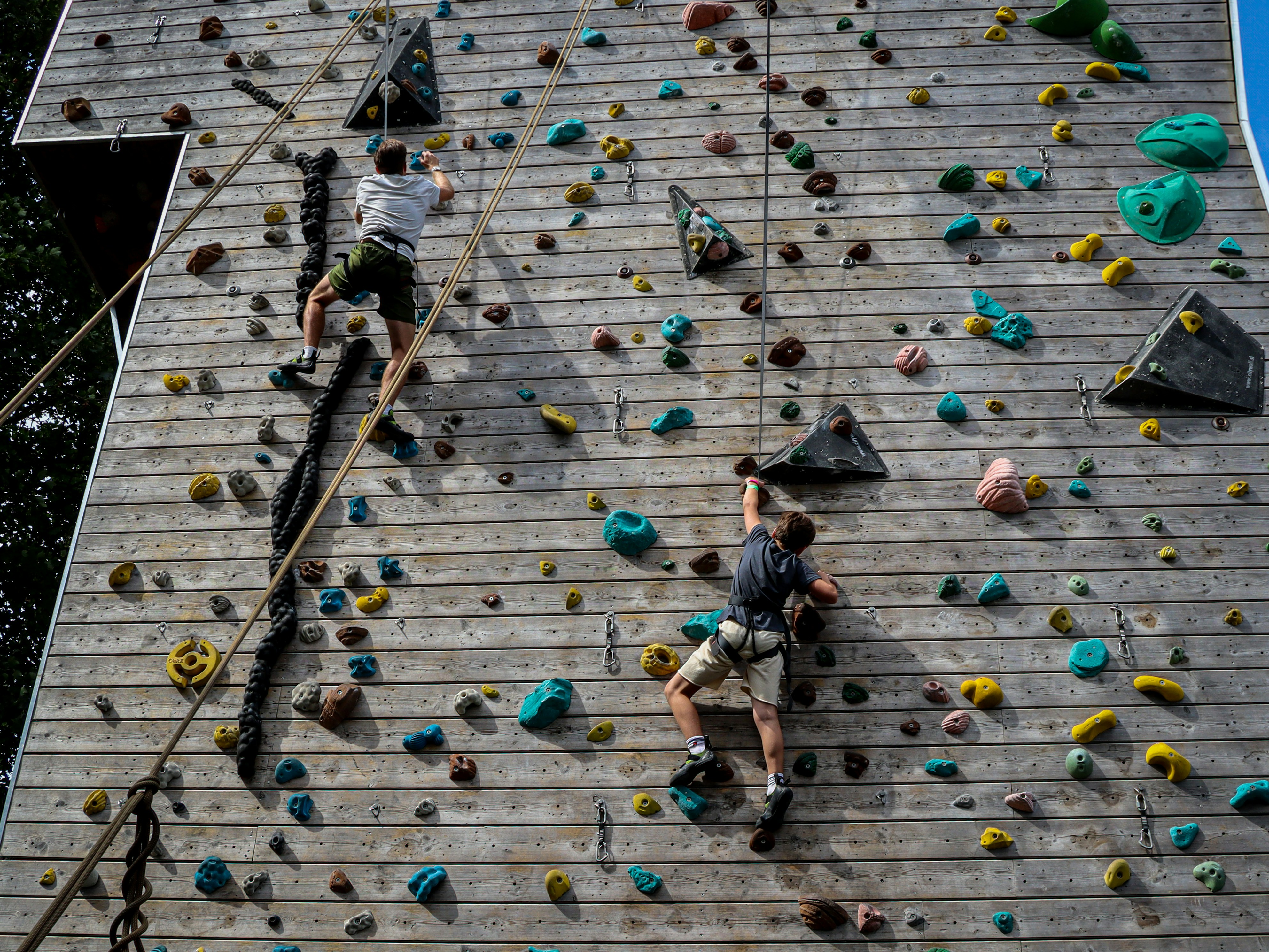 Two Climbers Conquering a Vertical Wall of Colorful Holds