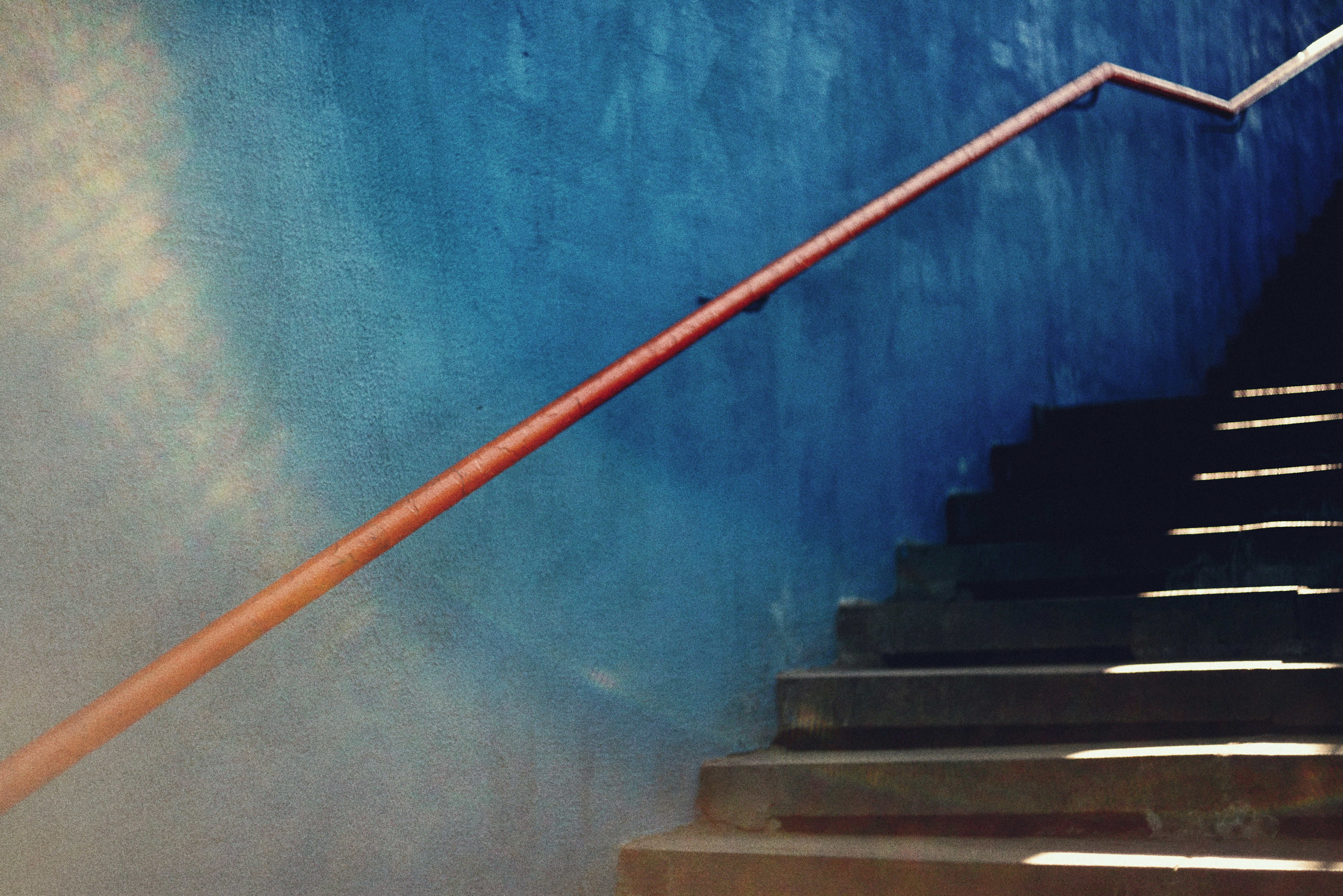 Blue Staircase Ascent Under Warm Handrail