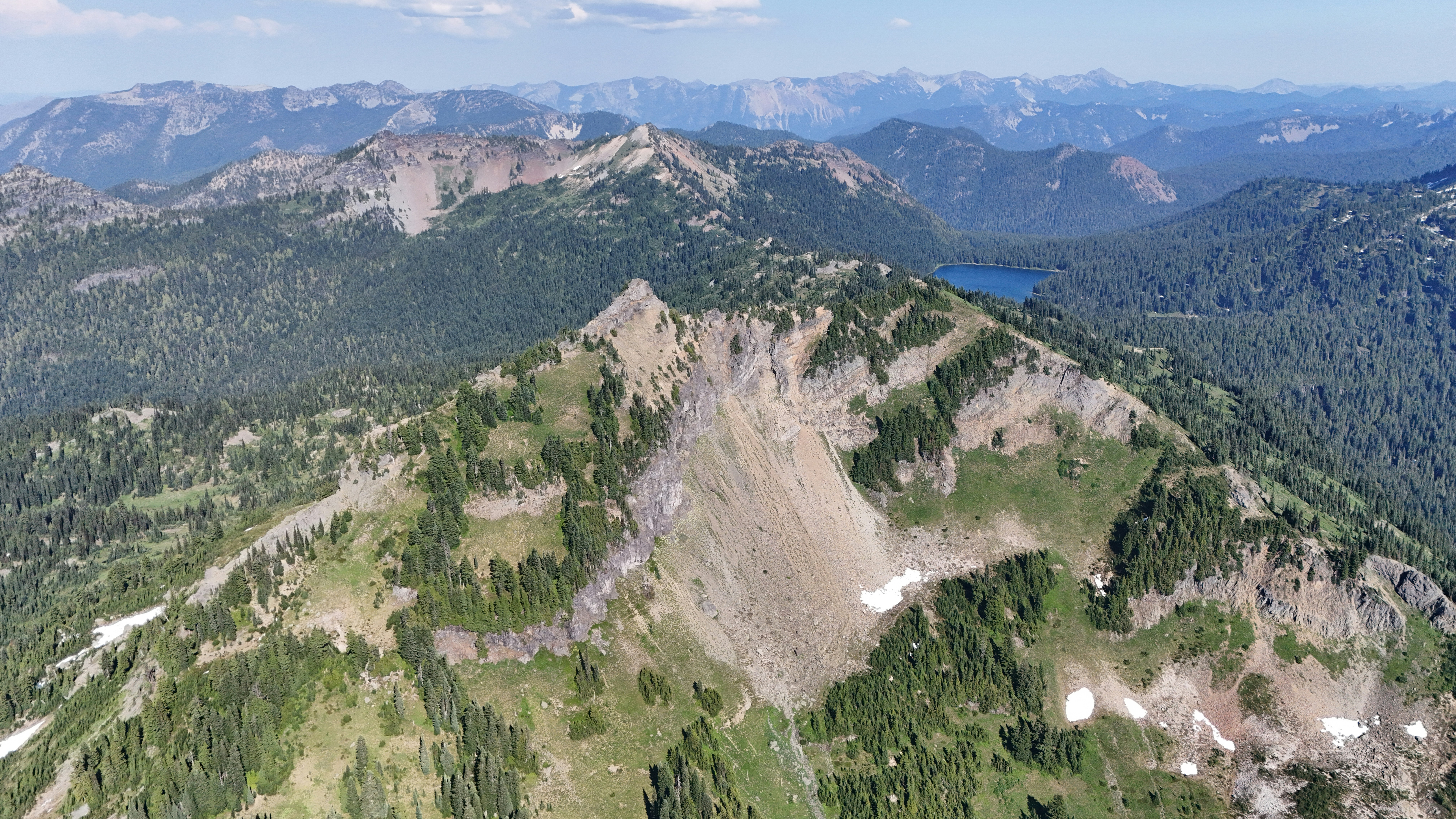 Verdant Ridge with Snow-kissed Flank Under Open Sky