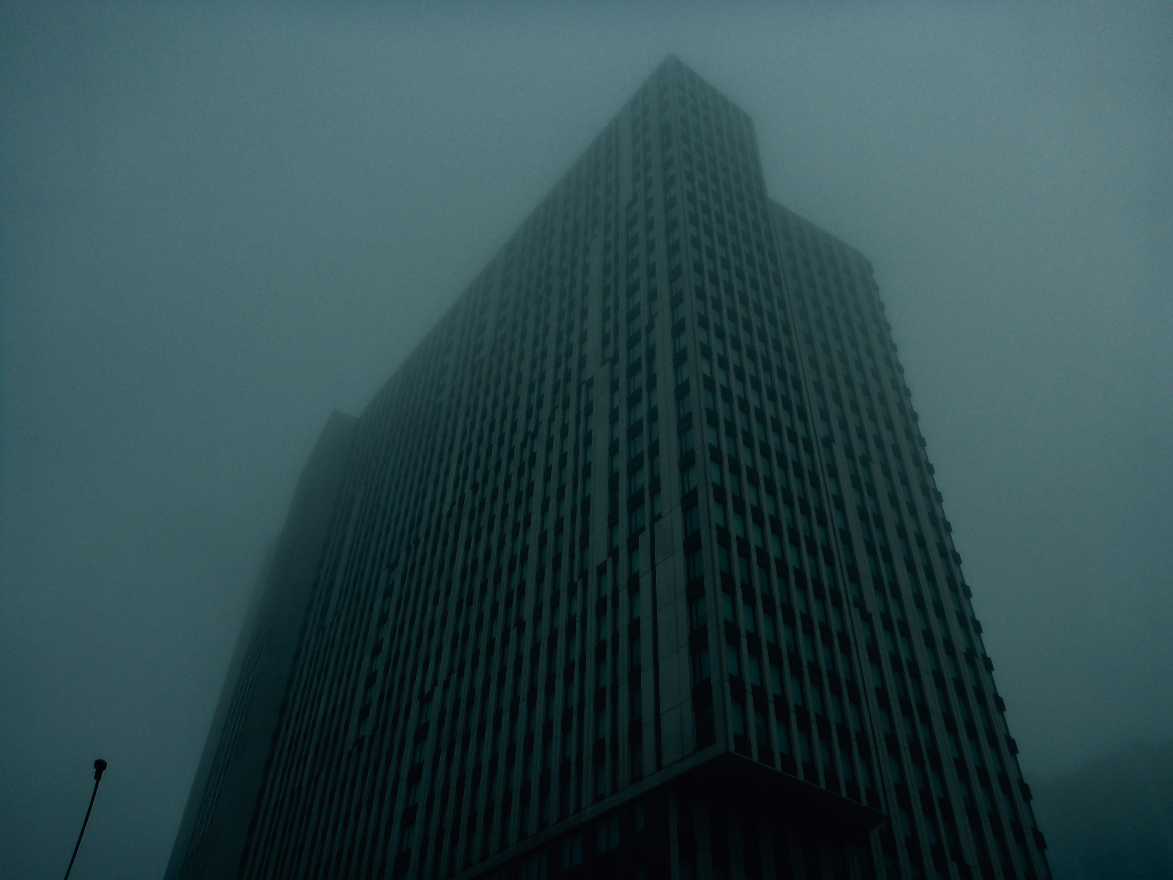 Midnight Monolith: A Fog-Wedged Skyscraper Reaches the Sky