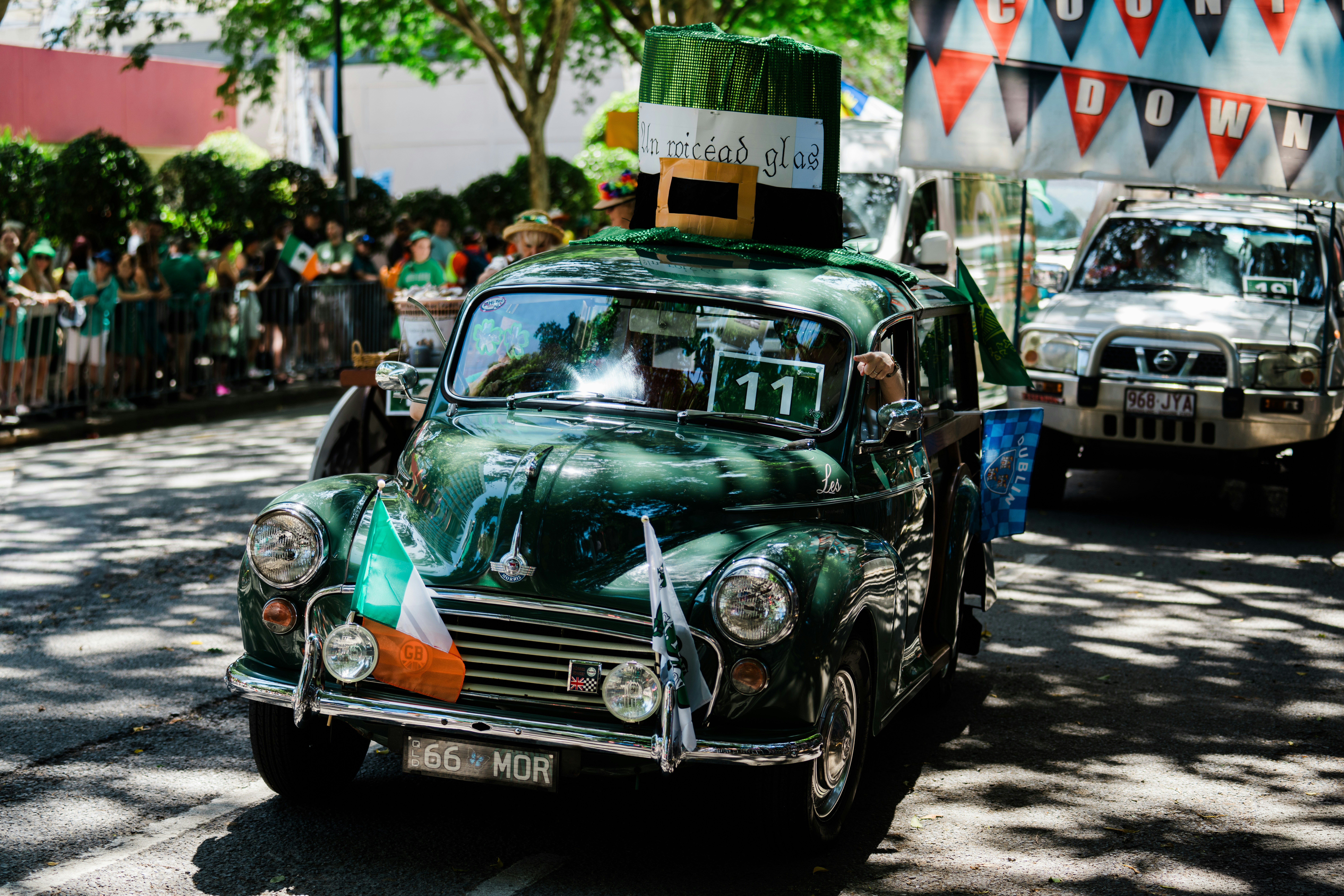 Vintage green car leads a lively parade under festive bunting