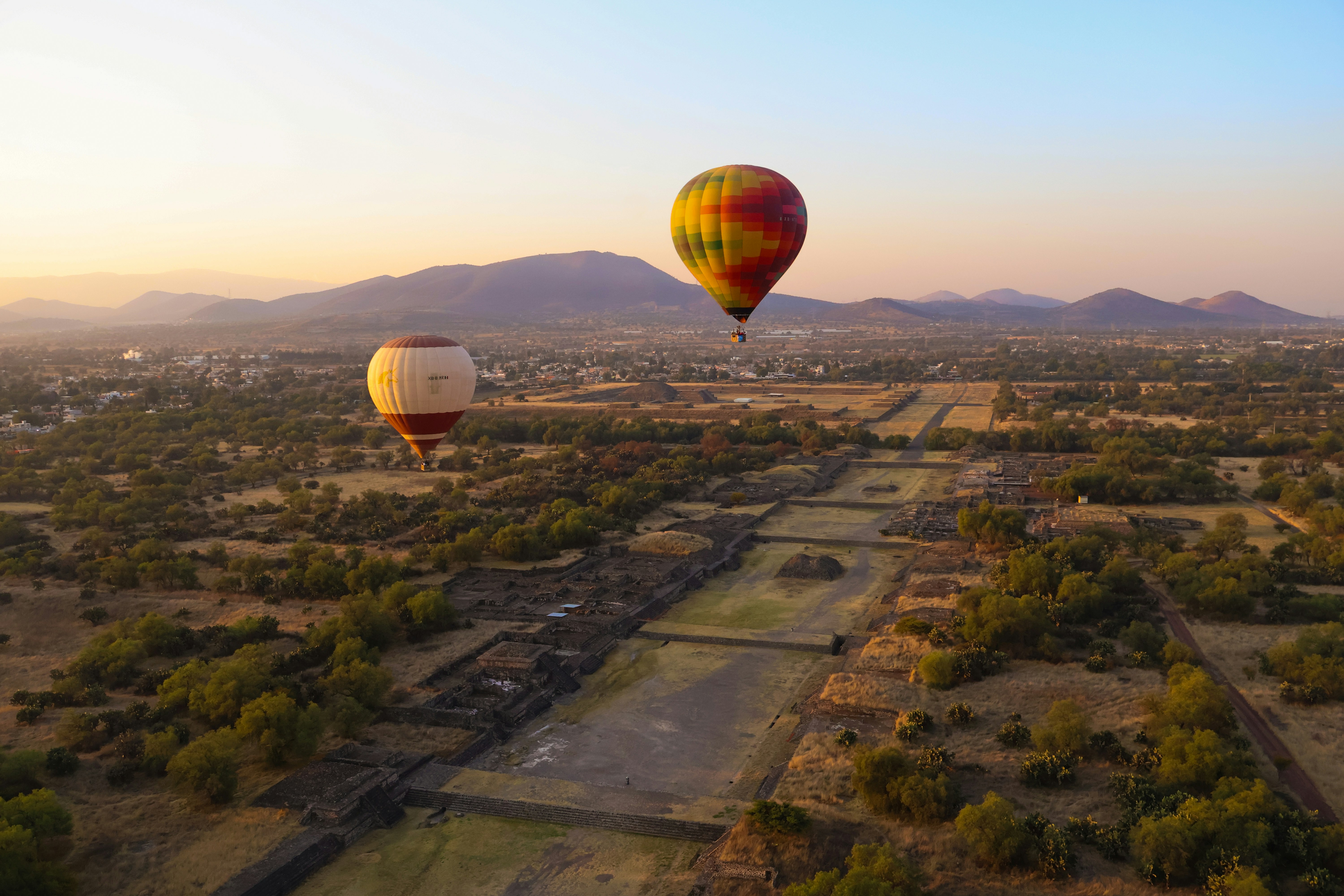 Golden Skyward: Balloons Over Arid Fields at Dusk