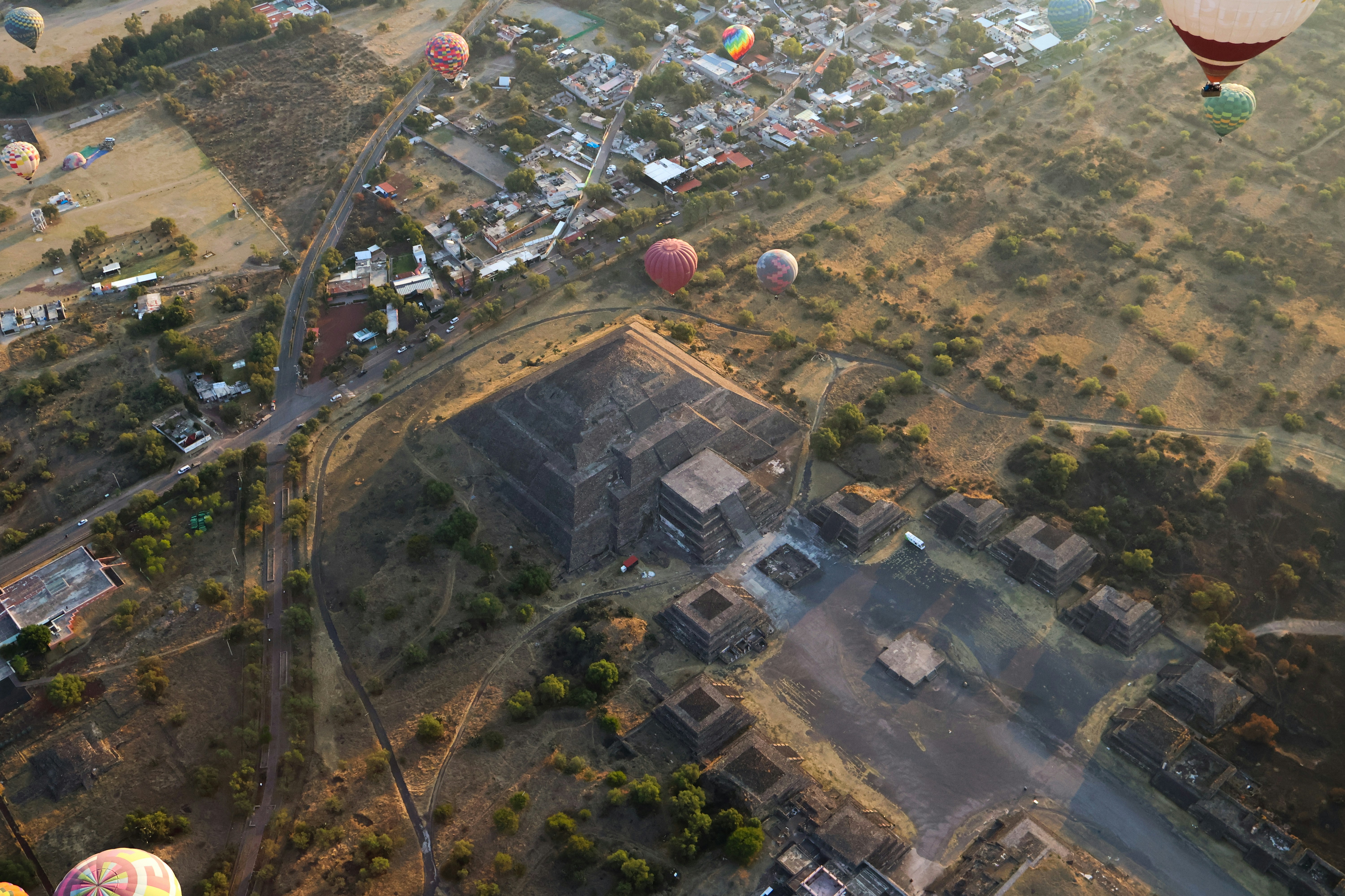 Aerial Panorama: Balloons Drift Over A Stone Monolith Village