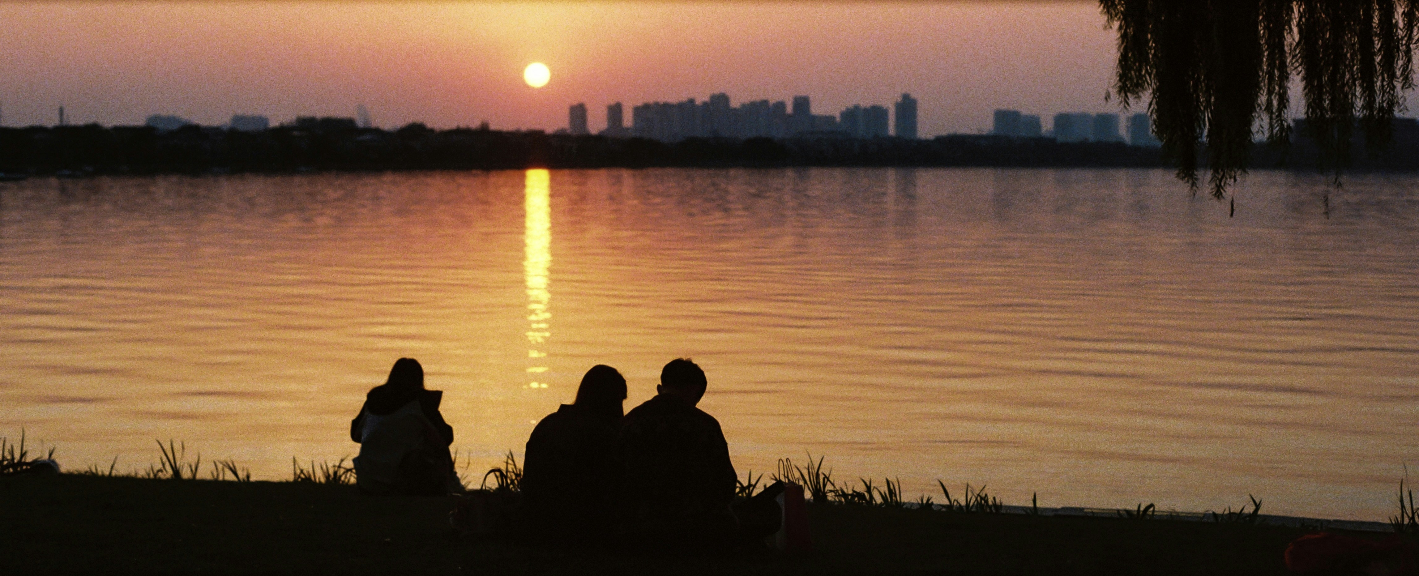 Silhouettes by the Riverside: Sunset Confluence