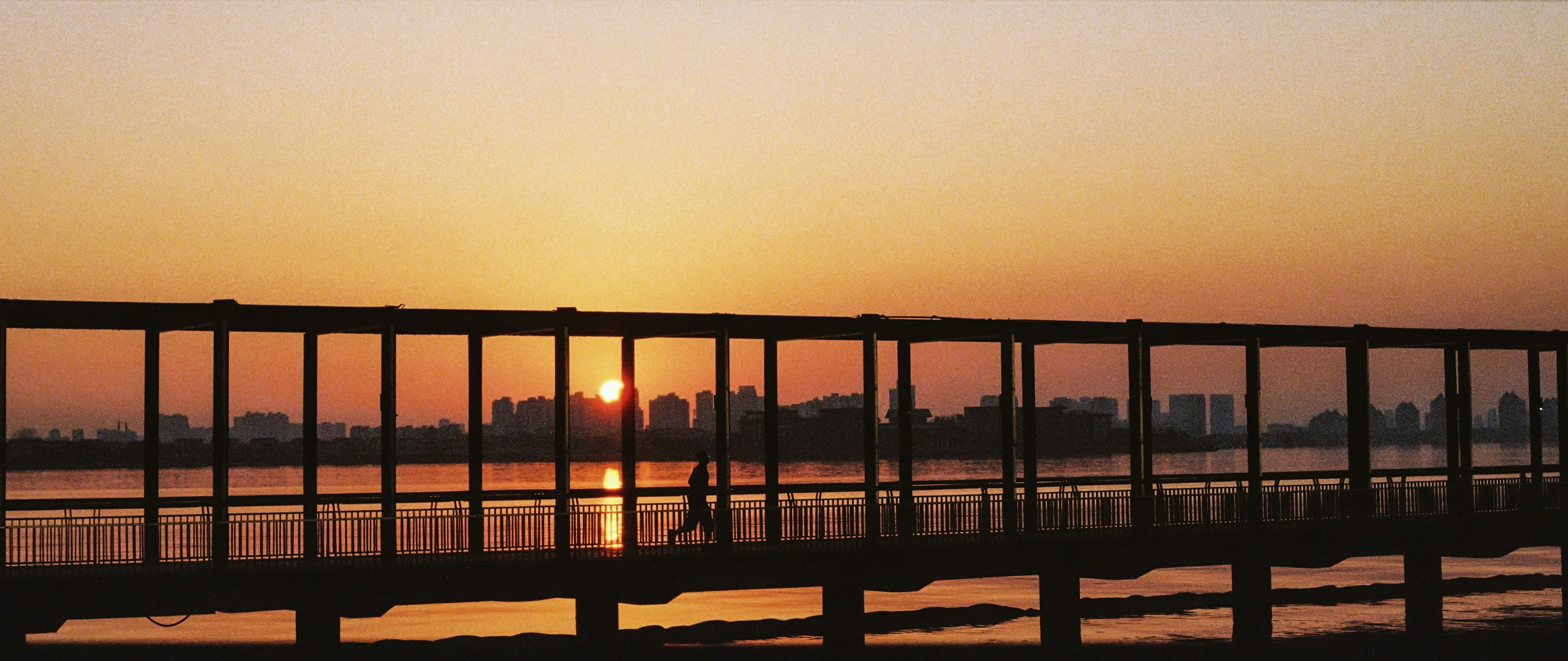 Sunset Over the Pier: A Silhouette Through the Railing