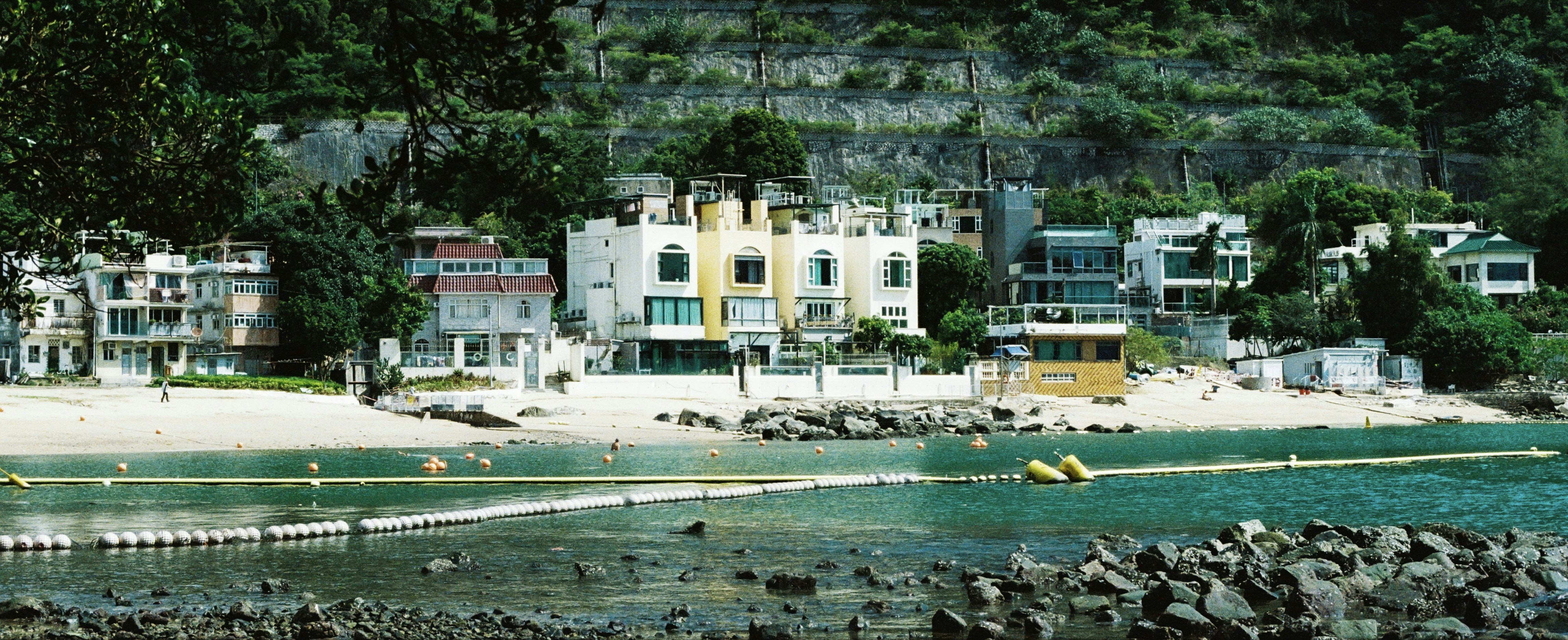 Colorful hillside cottages line a tranquil tropical shoreline