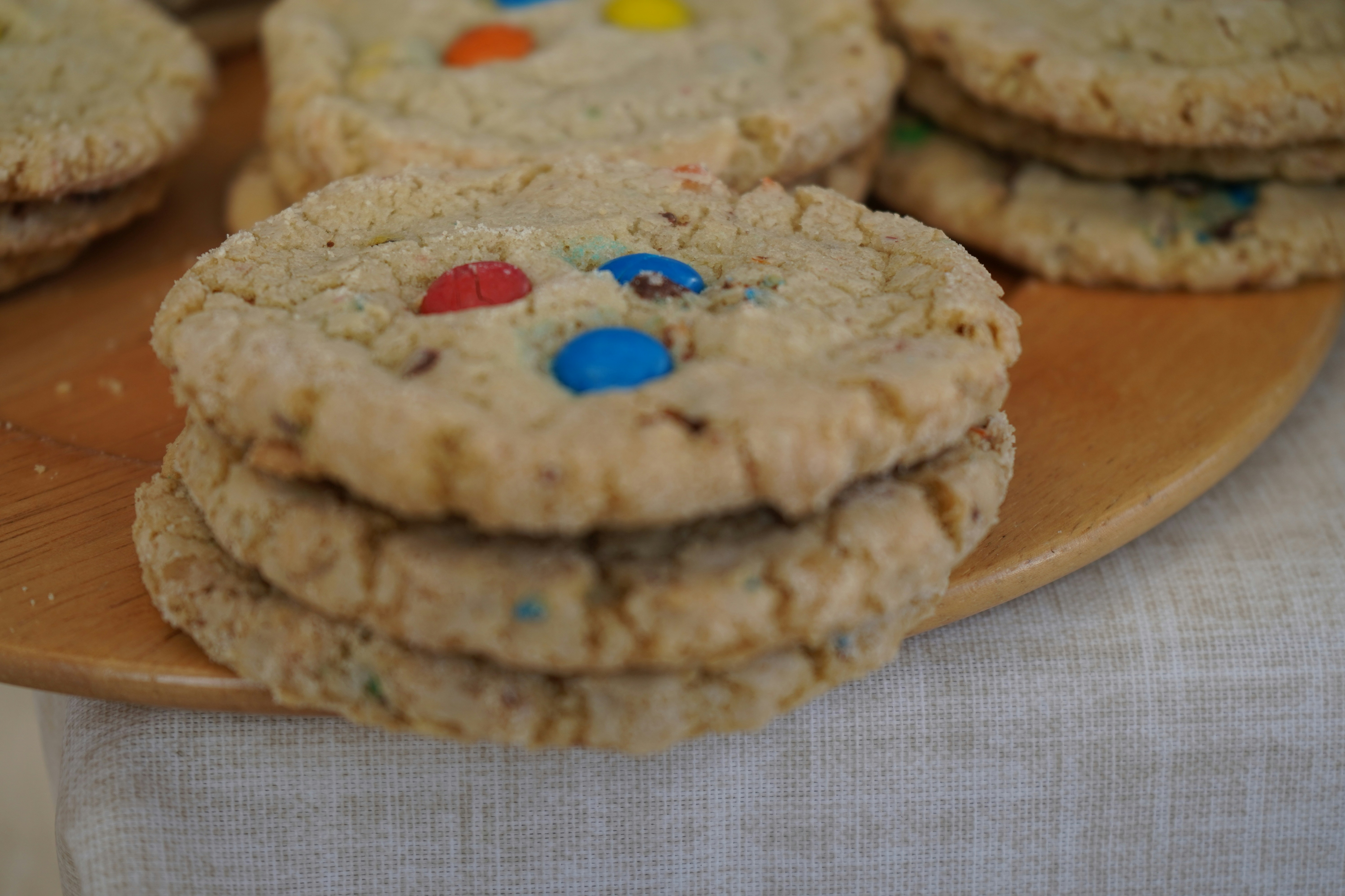 Stacked Sugar Cookies with Colorful Candies on a Wooden Plate