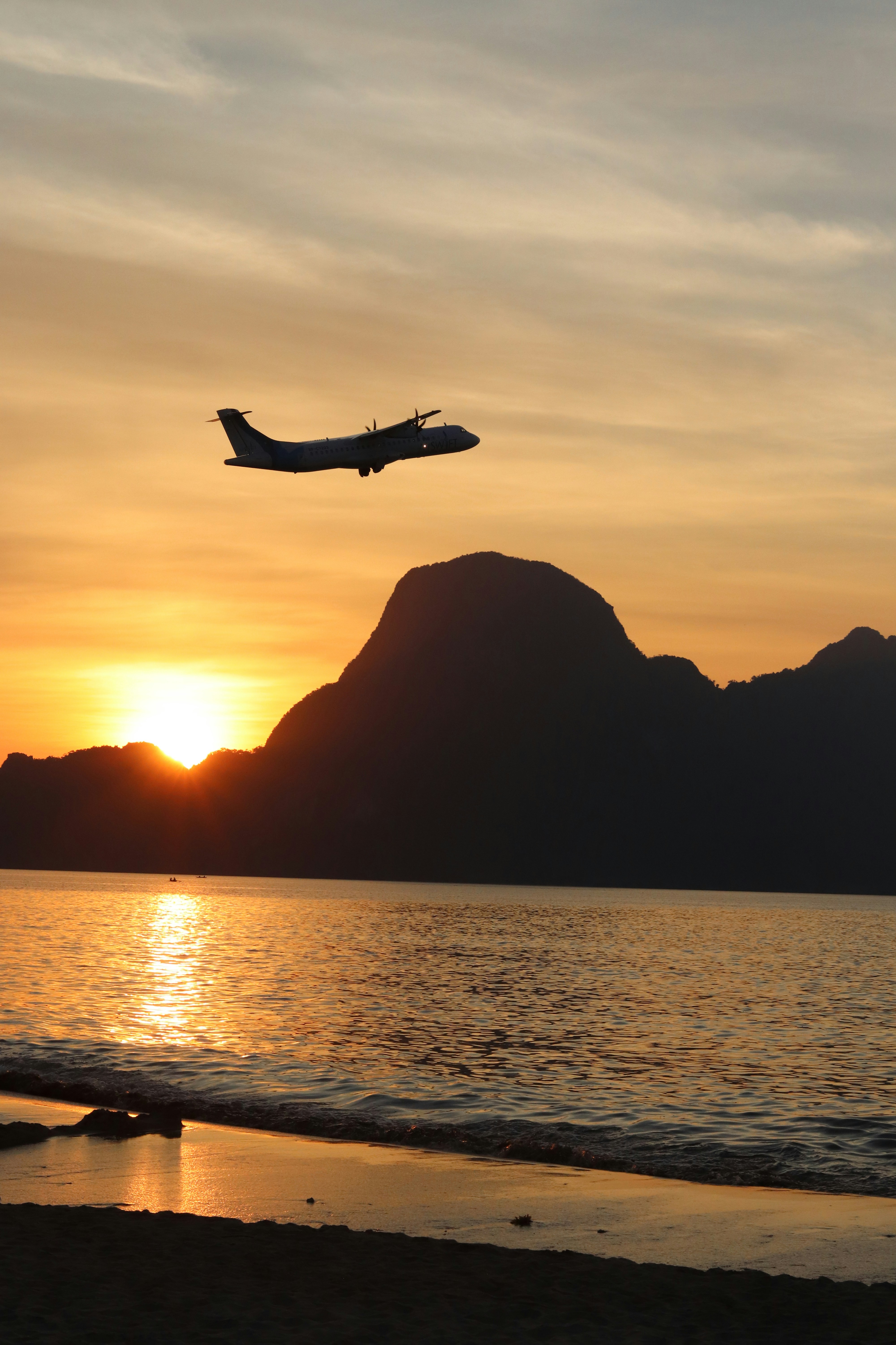Sunset Arrival: A lone turboprop over silhouetted cliffs at dusk