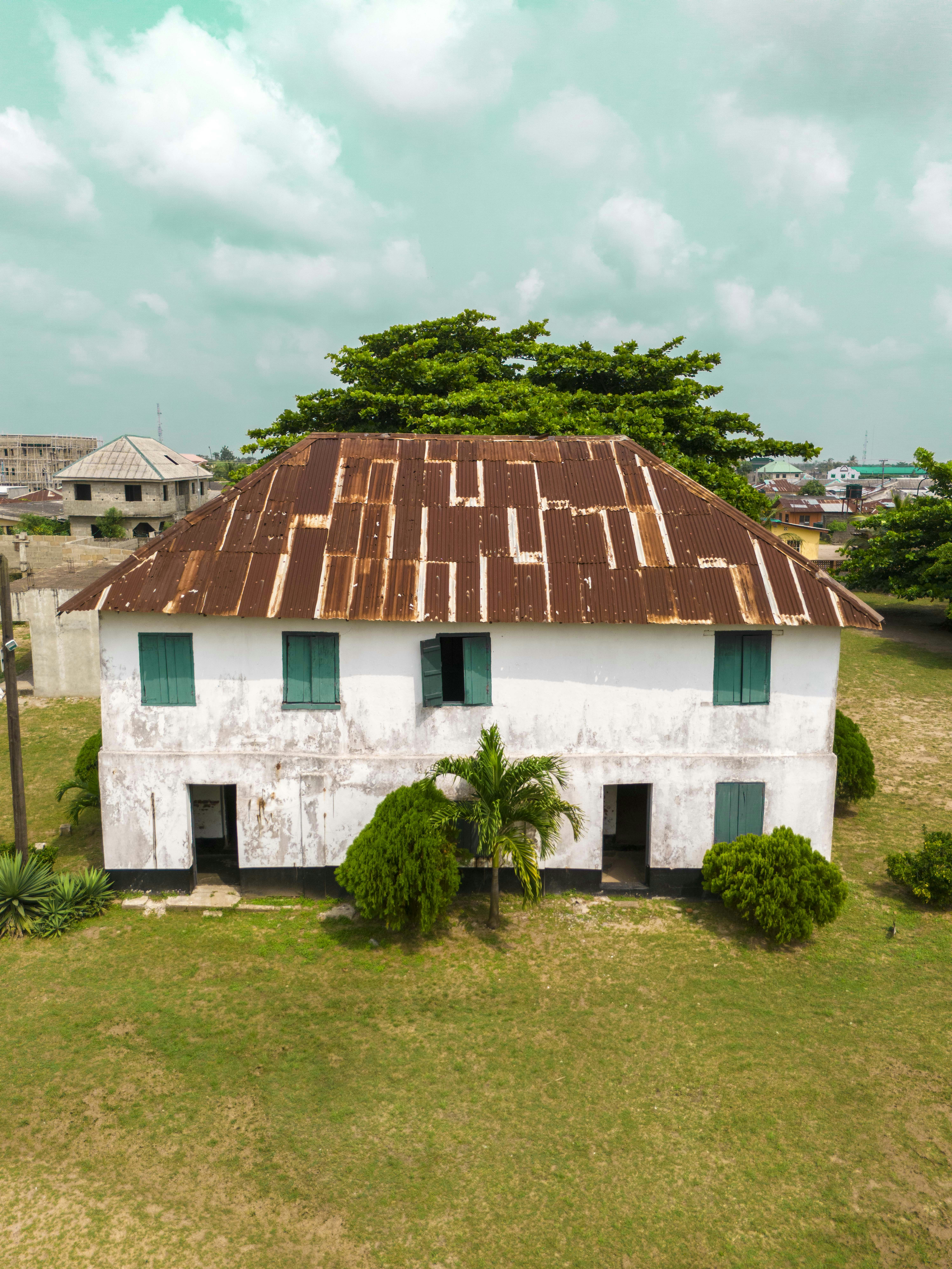 A Weathered Colonial House Guarded by Greenery