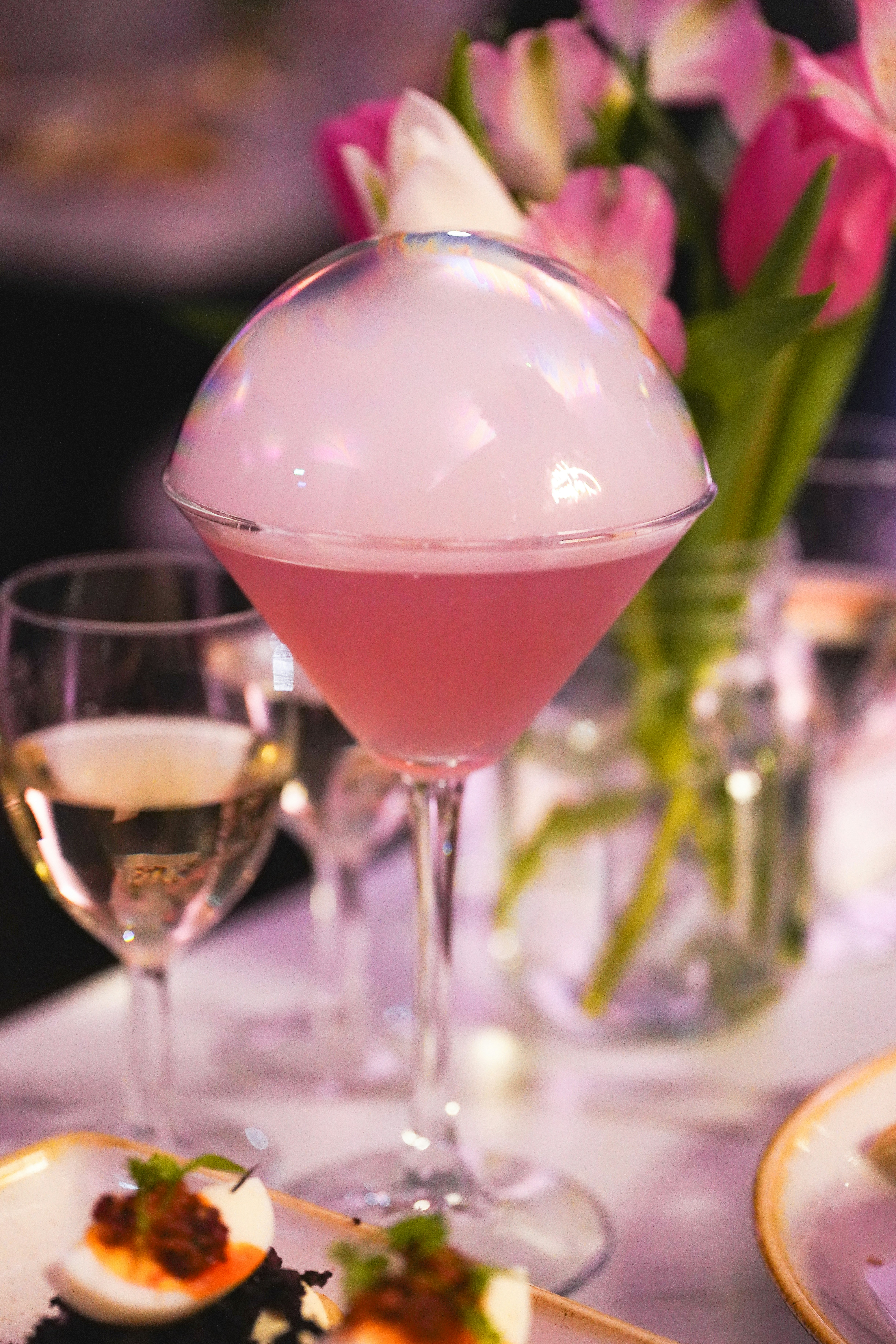 Bubble-glass centerpiece: a pink cocktail framed by tulips