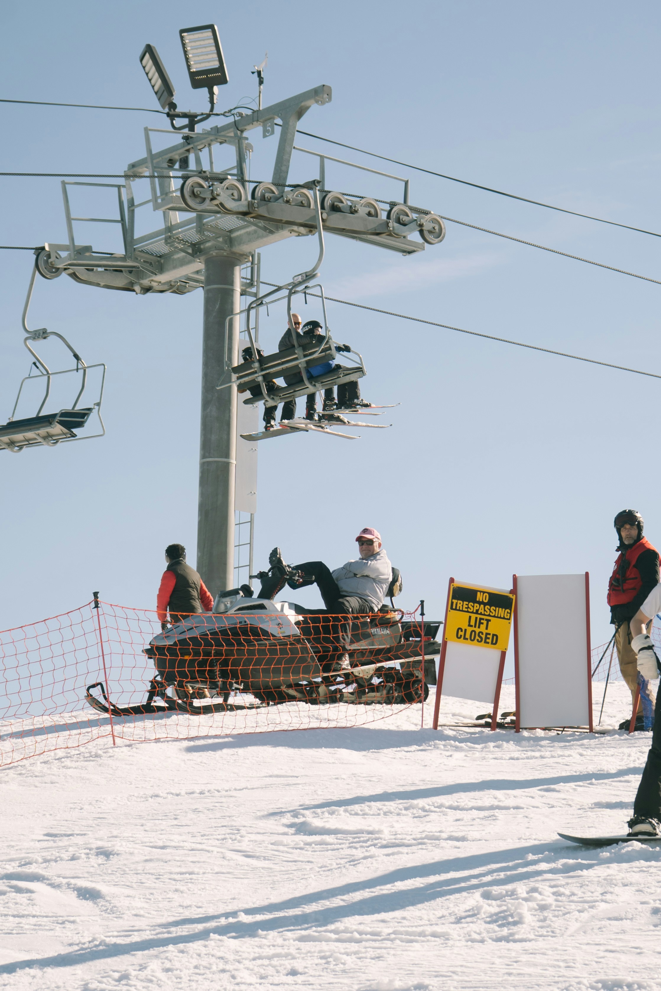 Chairlift Pause: Riders, Snow, and Steel under a Clear Sky