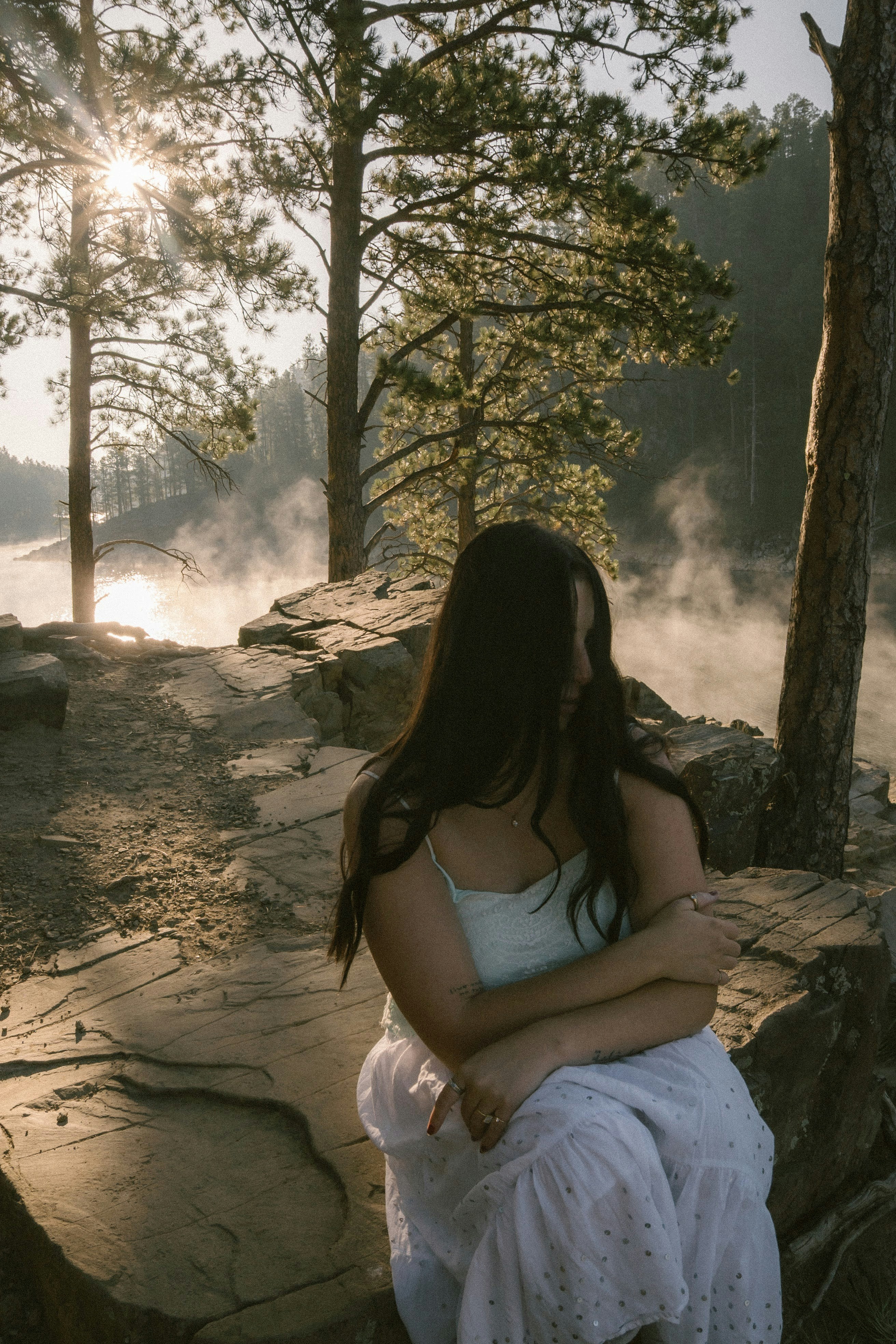 Sunlit Quiet: A Woman in White Amid Mist and Pines