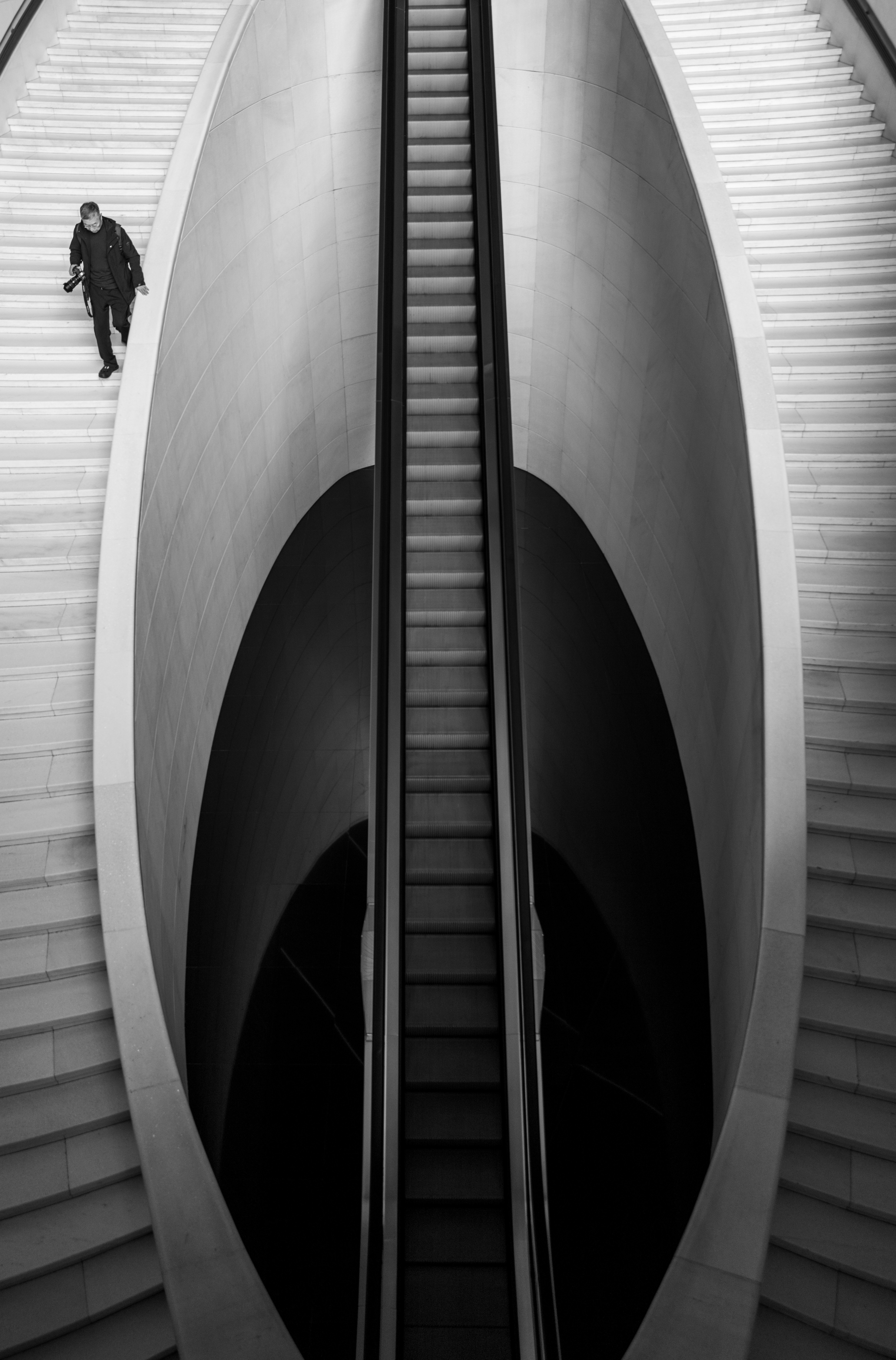 Escalator Spiral: A Lone Figure Ascending the Modern Void