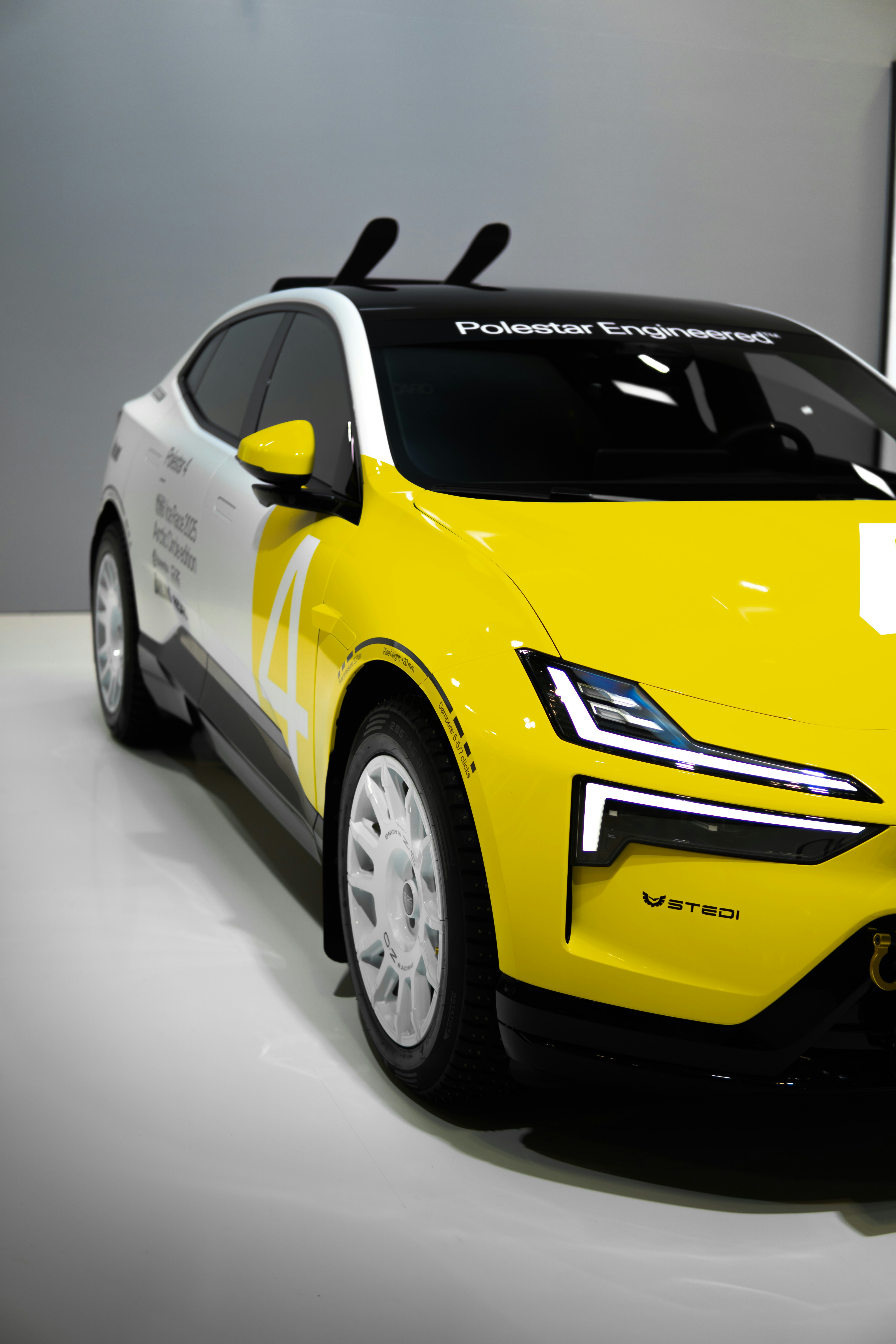 Yellow racecar emerges from a showroom glow, bold front fascia catching the light