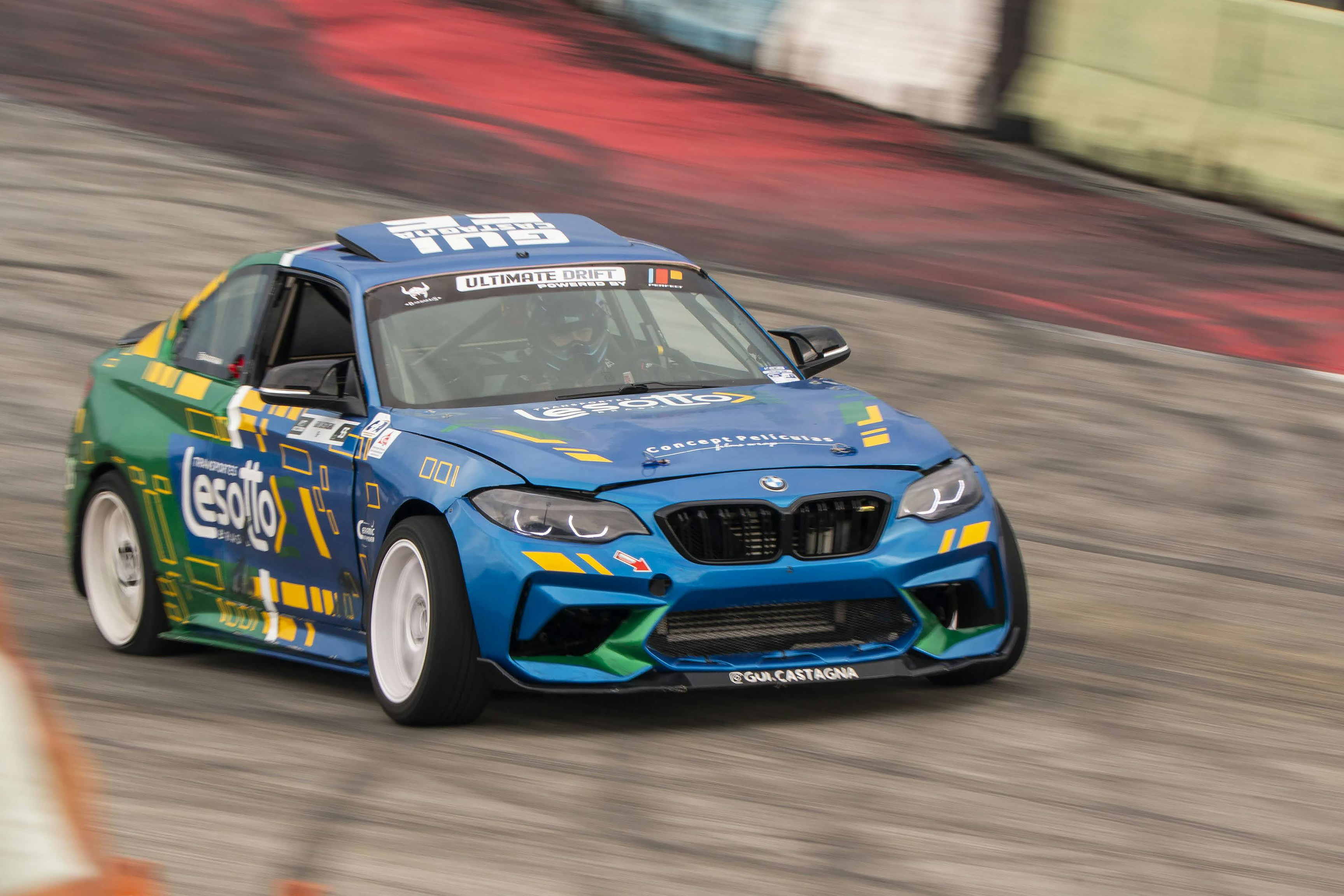 Blue and green race BMW in motion at a tight corner