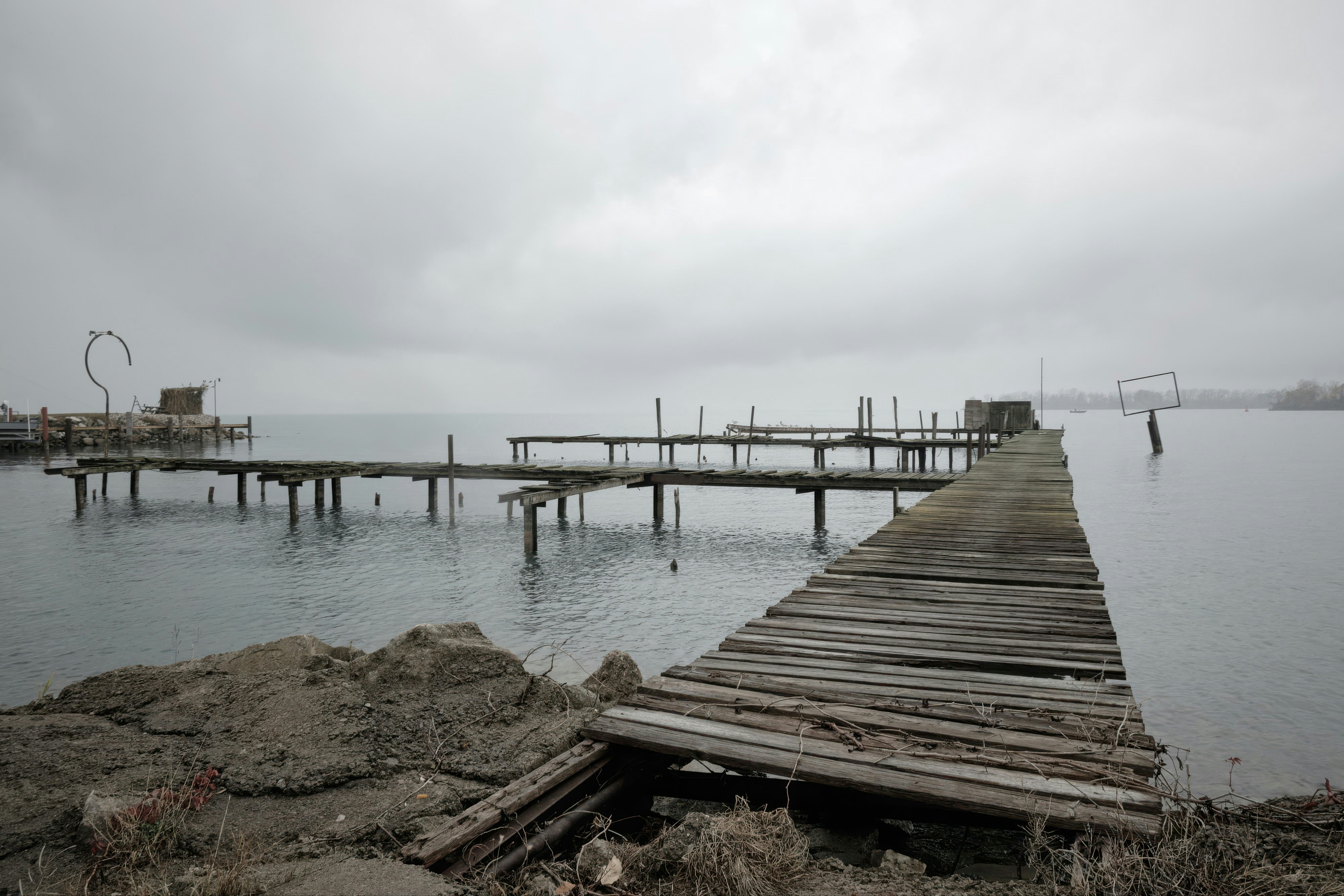 Verdant Silence: A Weathered Pier Reaches Toward A Chilly Horizon