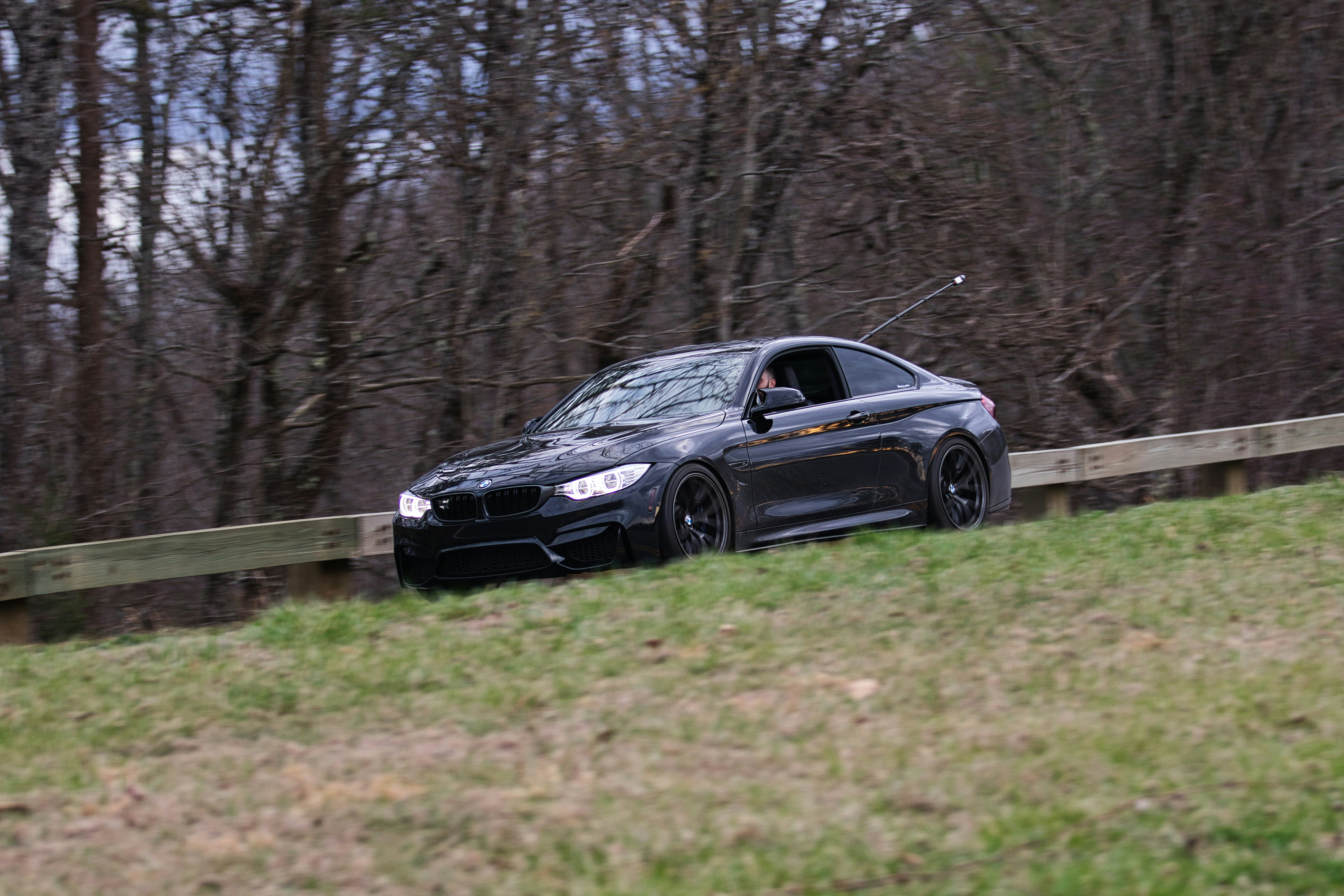 Mid-Field Pursuit: A Black Sports Car Races Along a Gentle Bend