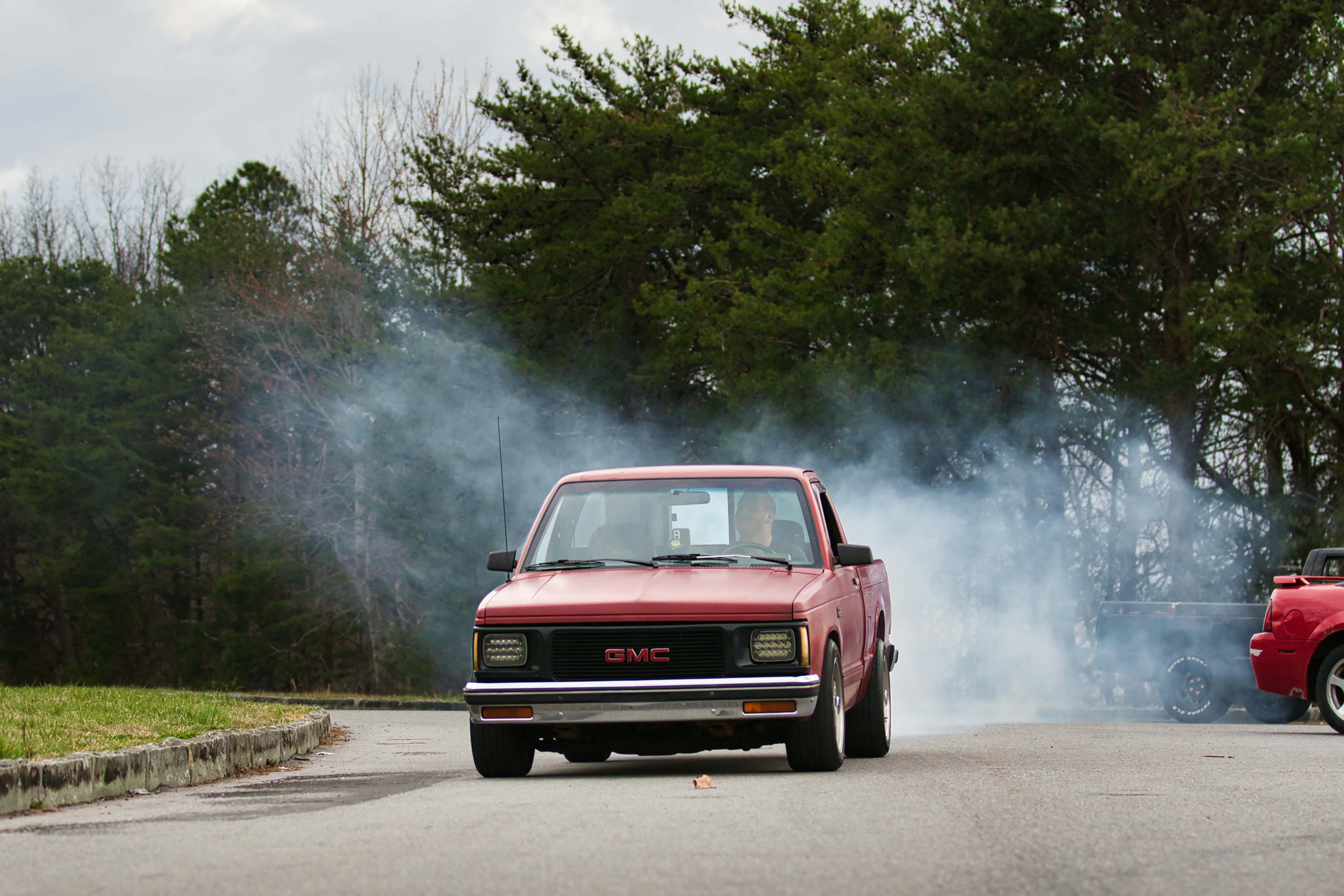Red GMC in a Quiet Wake: Smoke Trails and Autumn Roads