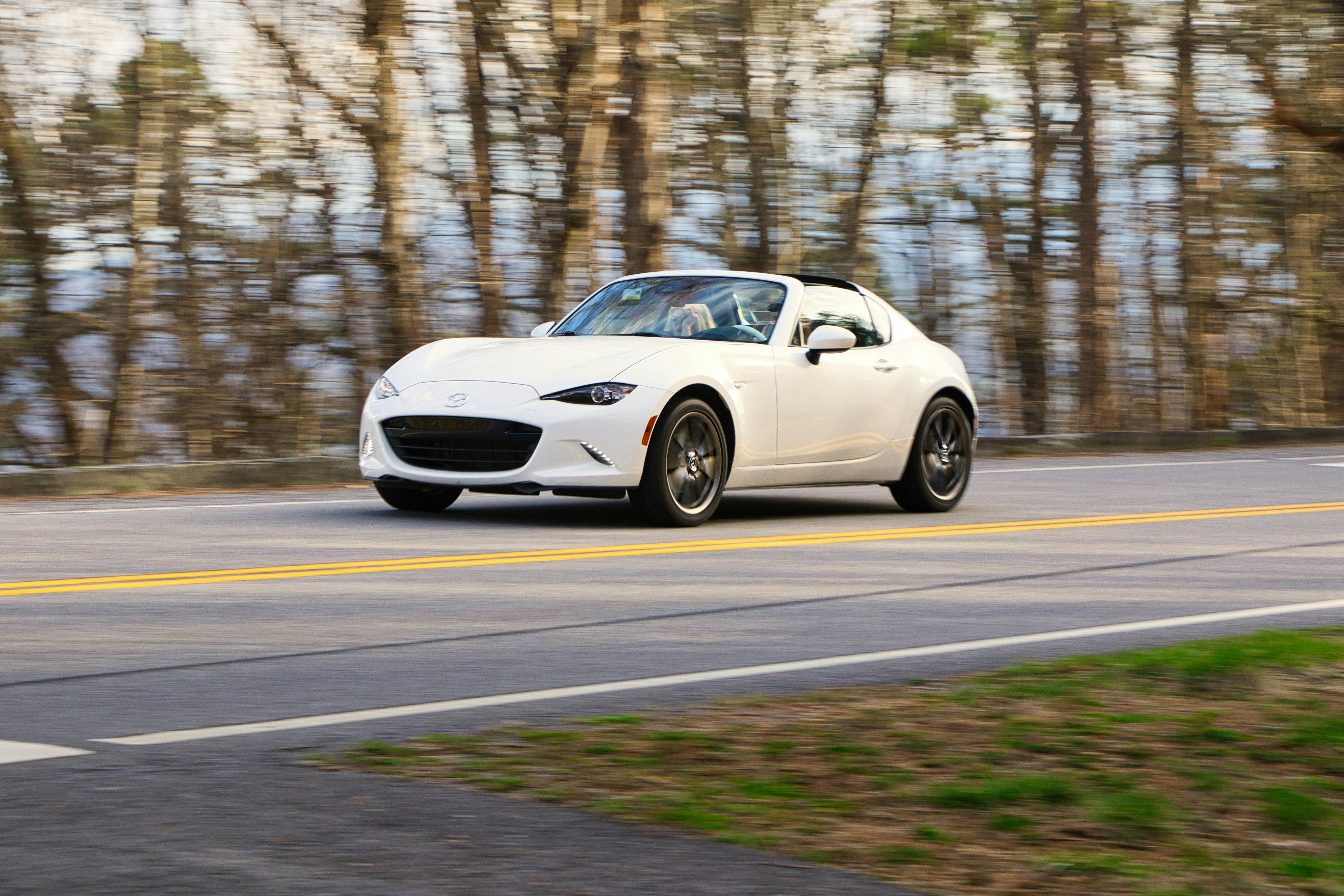 White Jaguar Convertible in Motion Along a Quiet Rivertown Road