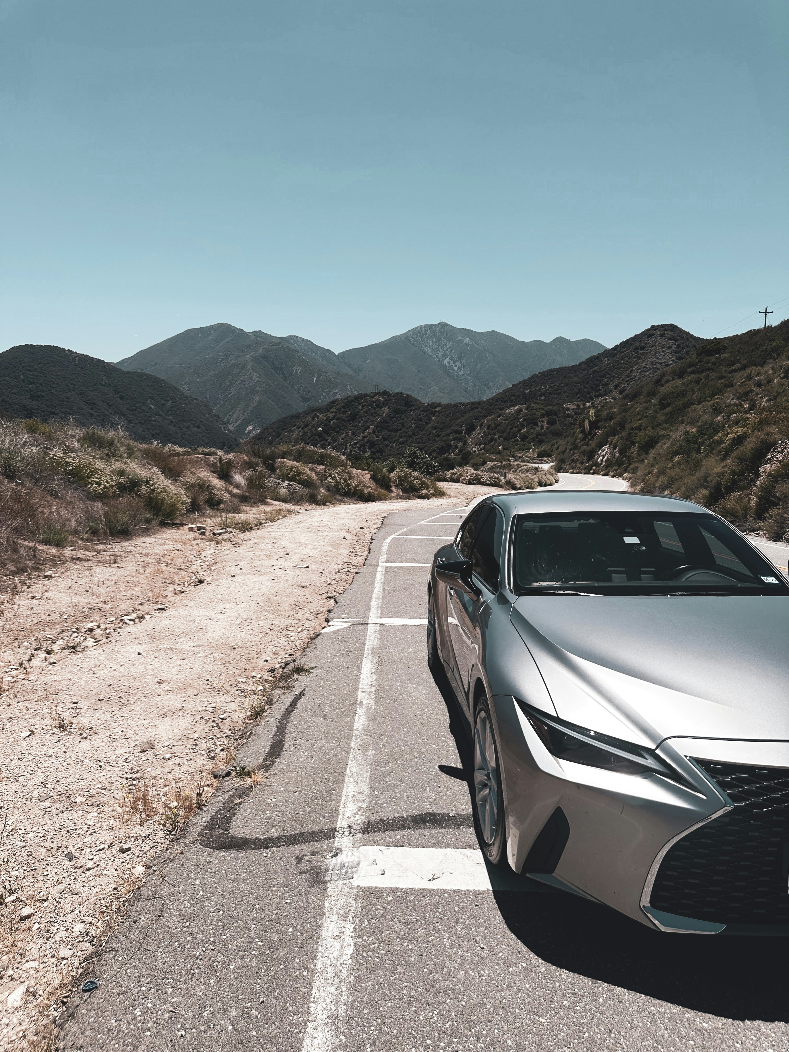 Silver sedan leading the winding desert road toward rugged mountains