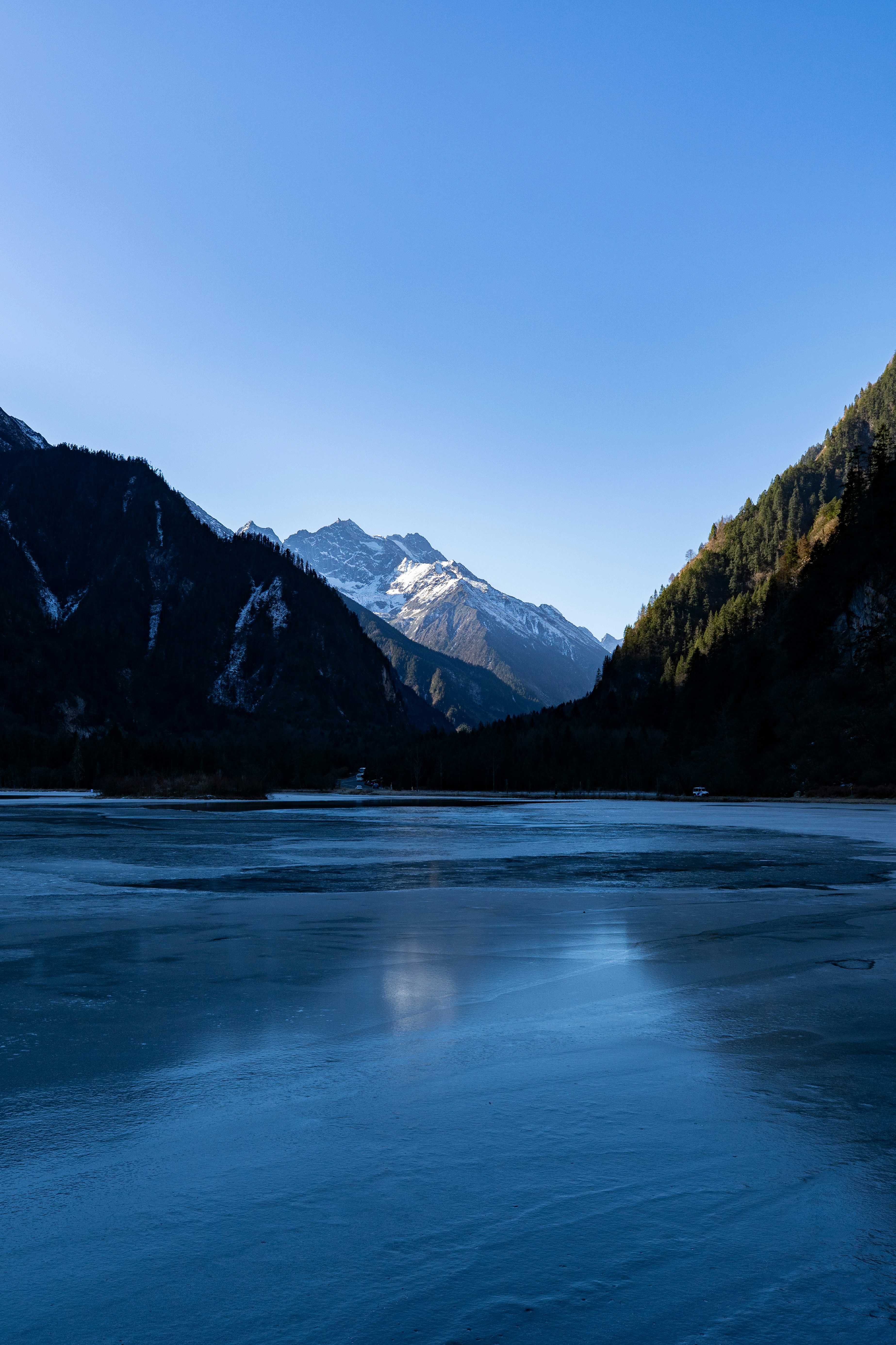 Glacial Blue Corridor: A Mountain Pass Framed by Frozen Lake