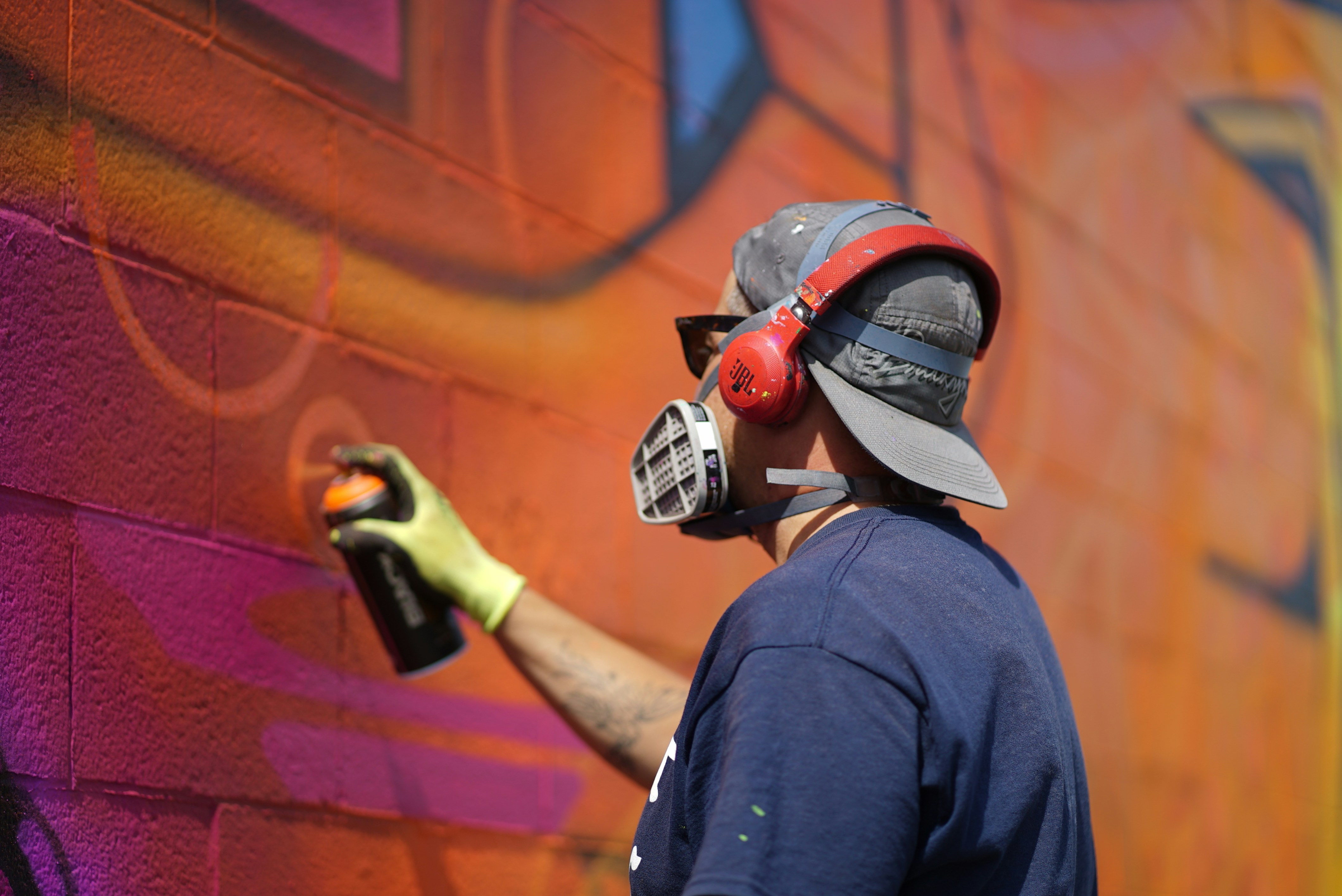 Graffiti Artist in a Colorful Scene: Spray, Shield, and Spray-painted Walls