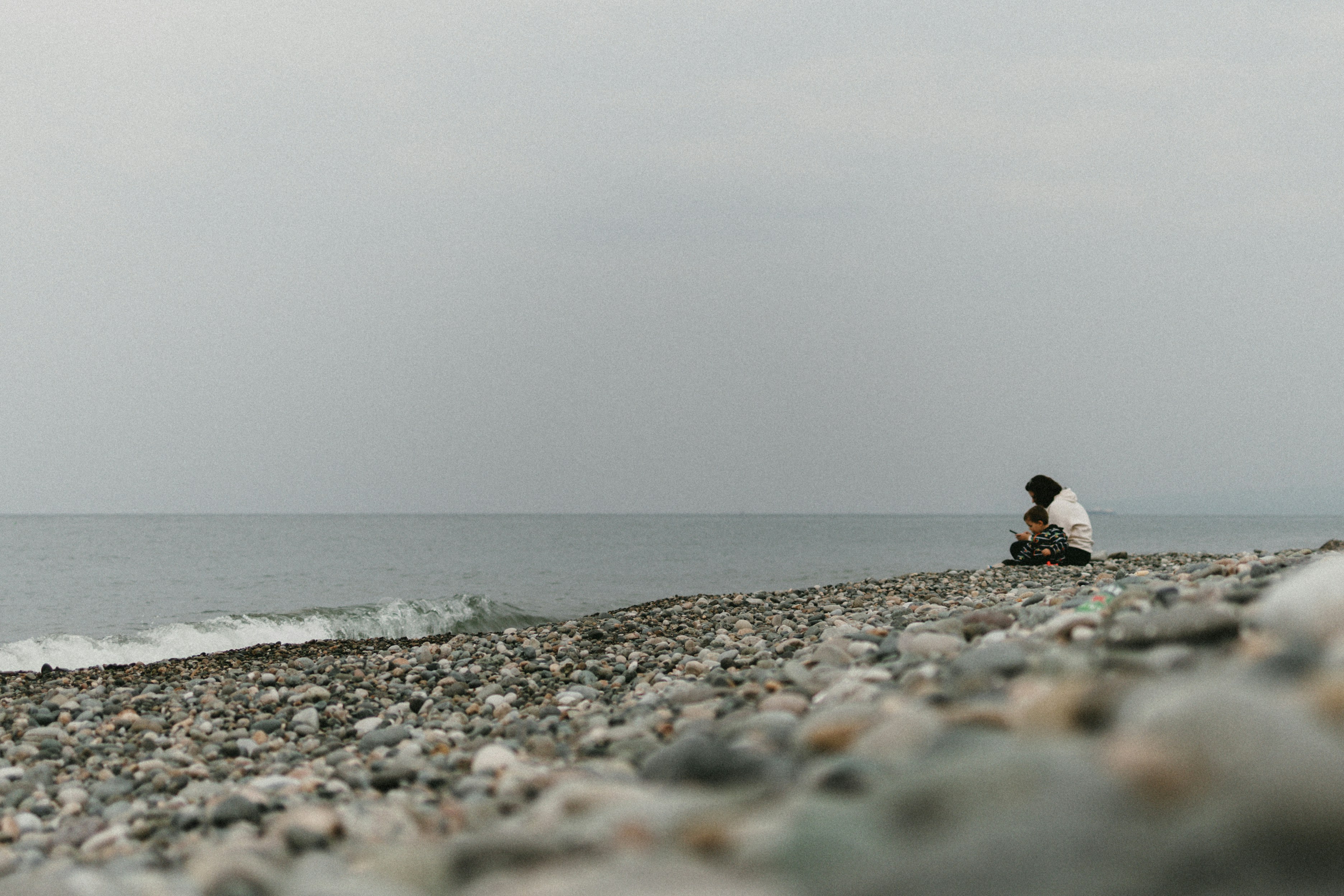 Pebble shoreline vignette: a lone figure by the sea