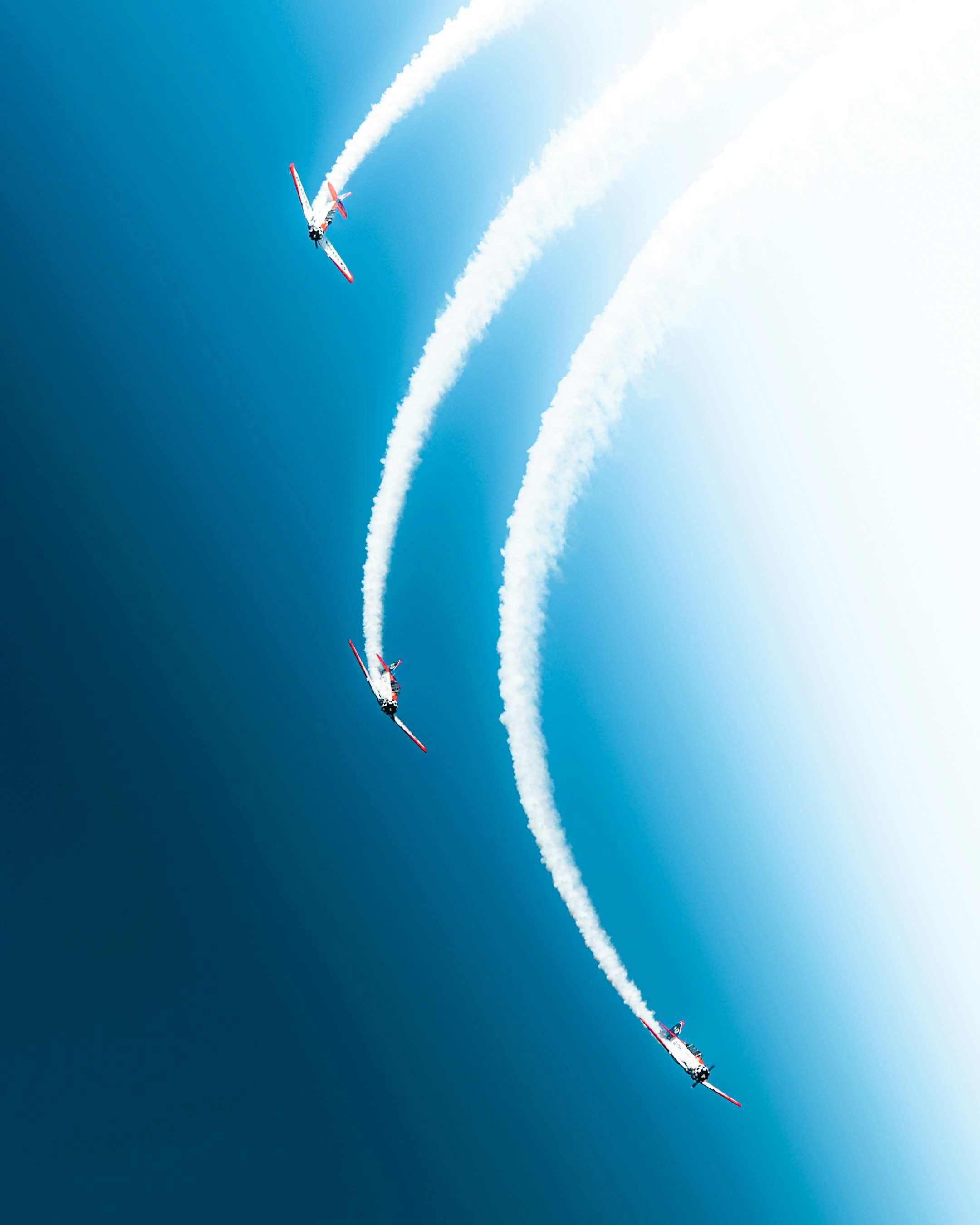 Aerobatic Traces: Twin Wings Carve White Arcs Across Deep Blue Sky
