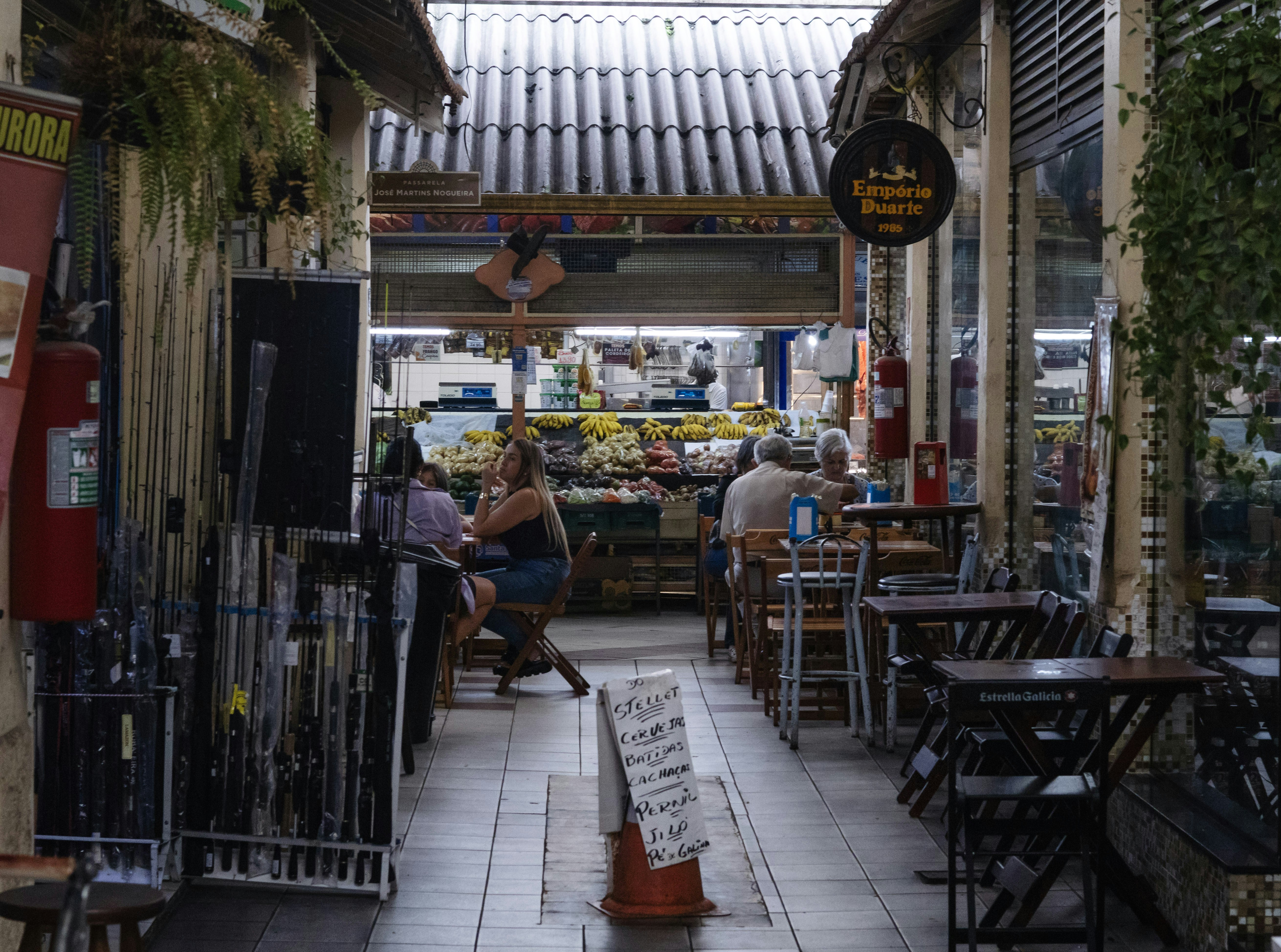 Sunlit Café Corridor Framing a Busy Market Inside