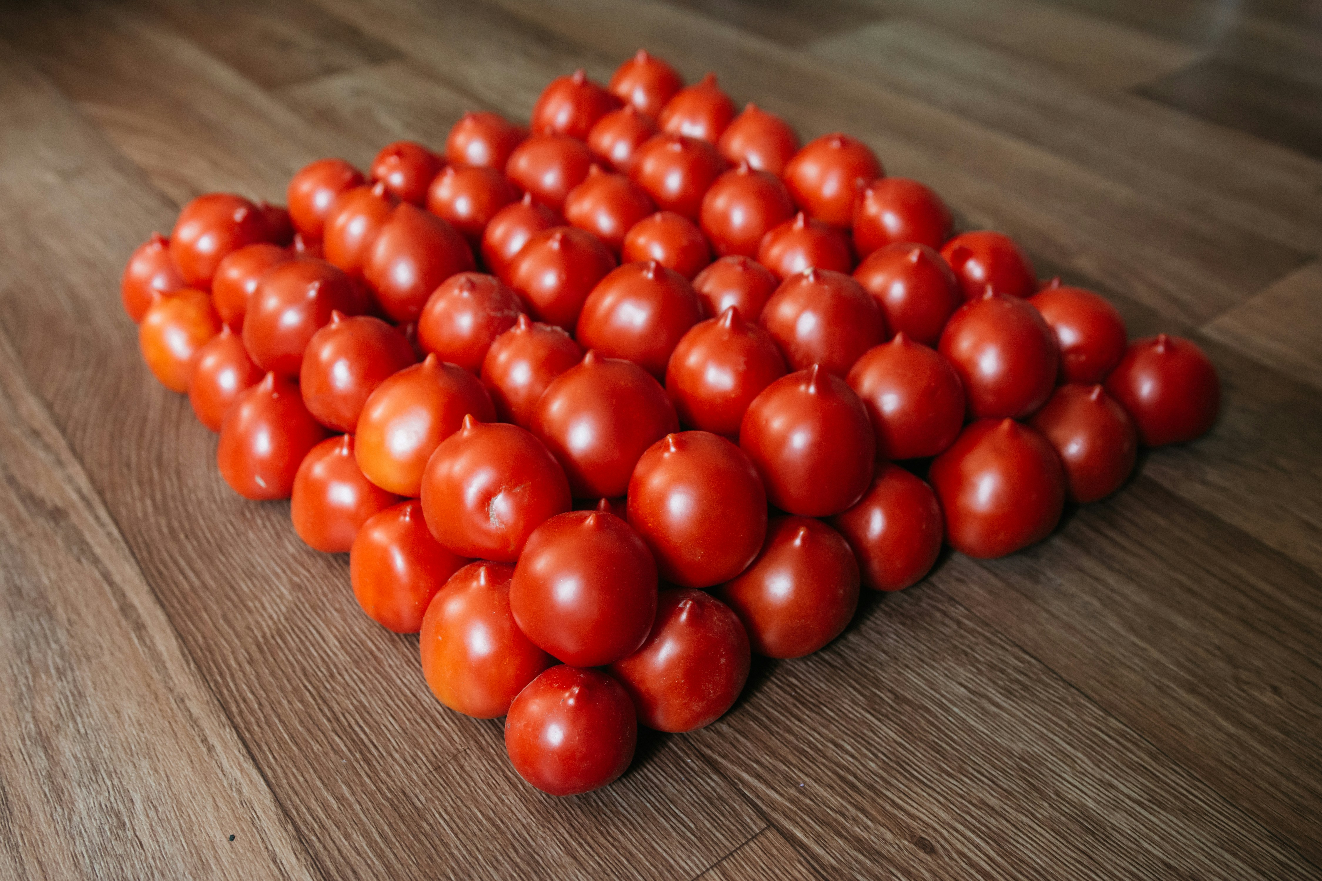 Red Bell Peppers? No—grid of glossy red spheres on a wooden floor