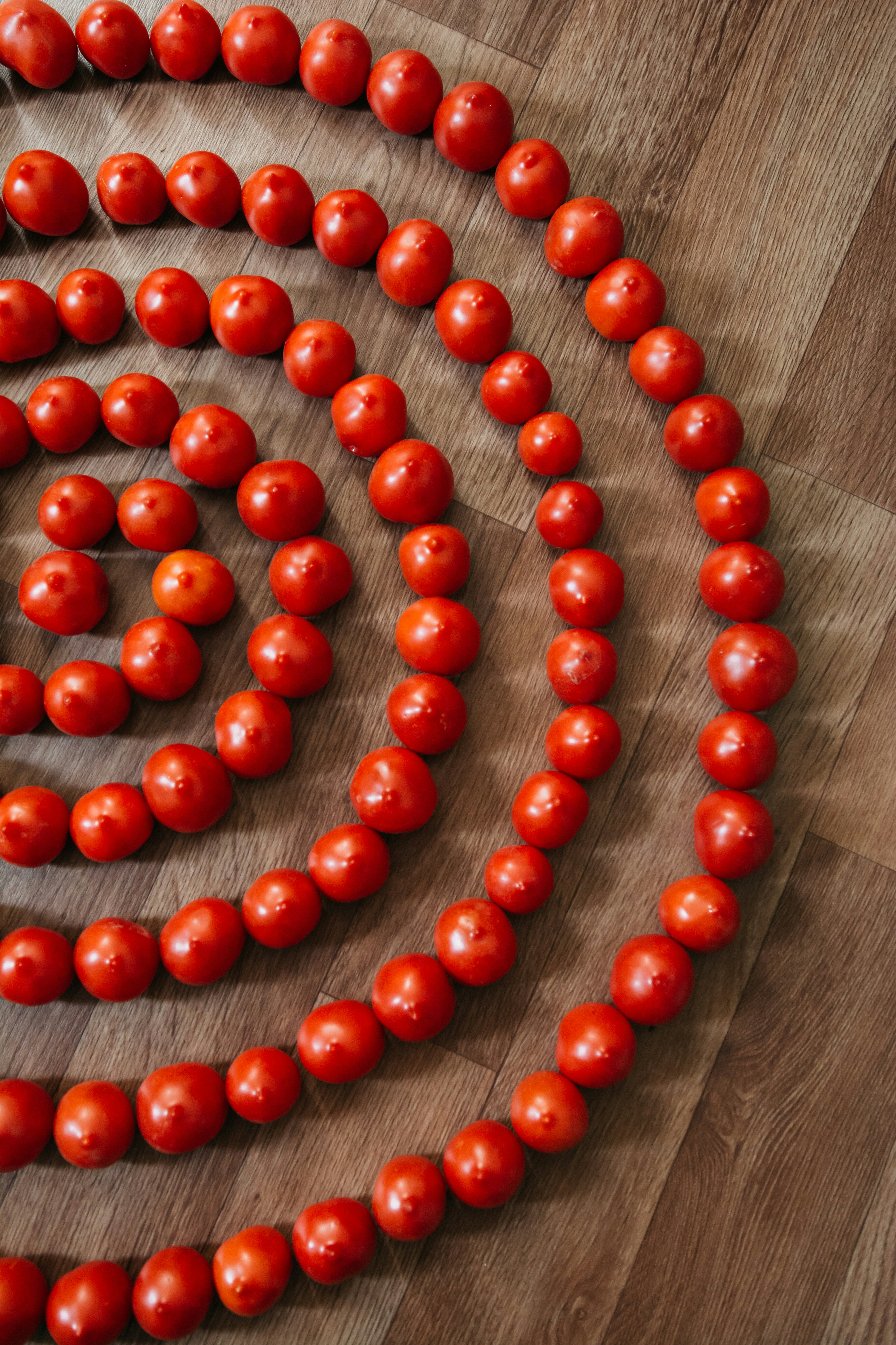 Vivid Red Orbits: A Spiral of Cherry Tomatoes on Wood