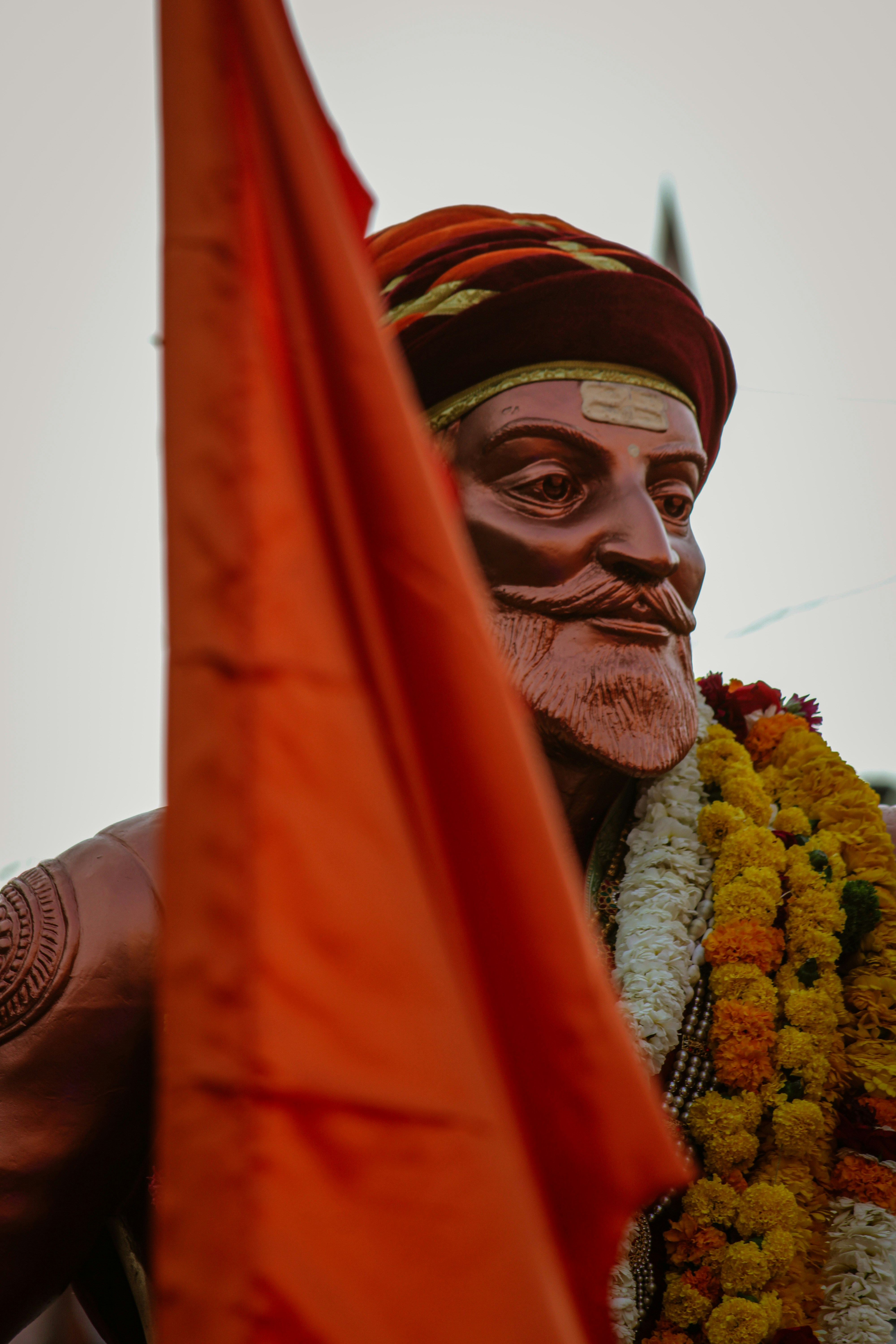 Garlanded Statue Revealed Behind a Rich Orange Drape