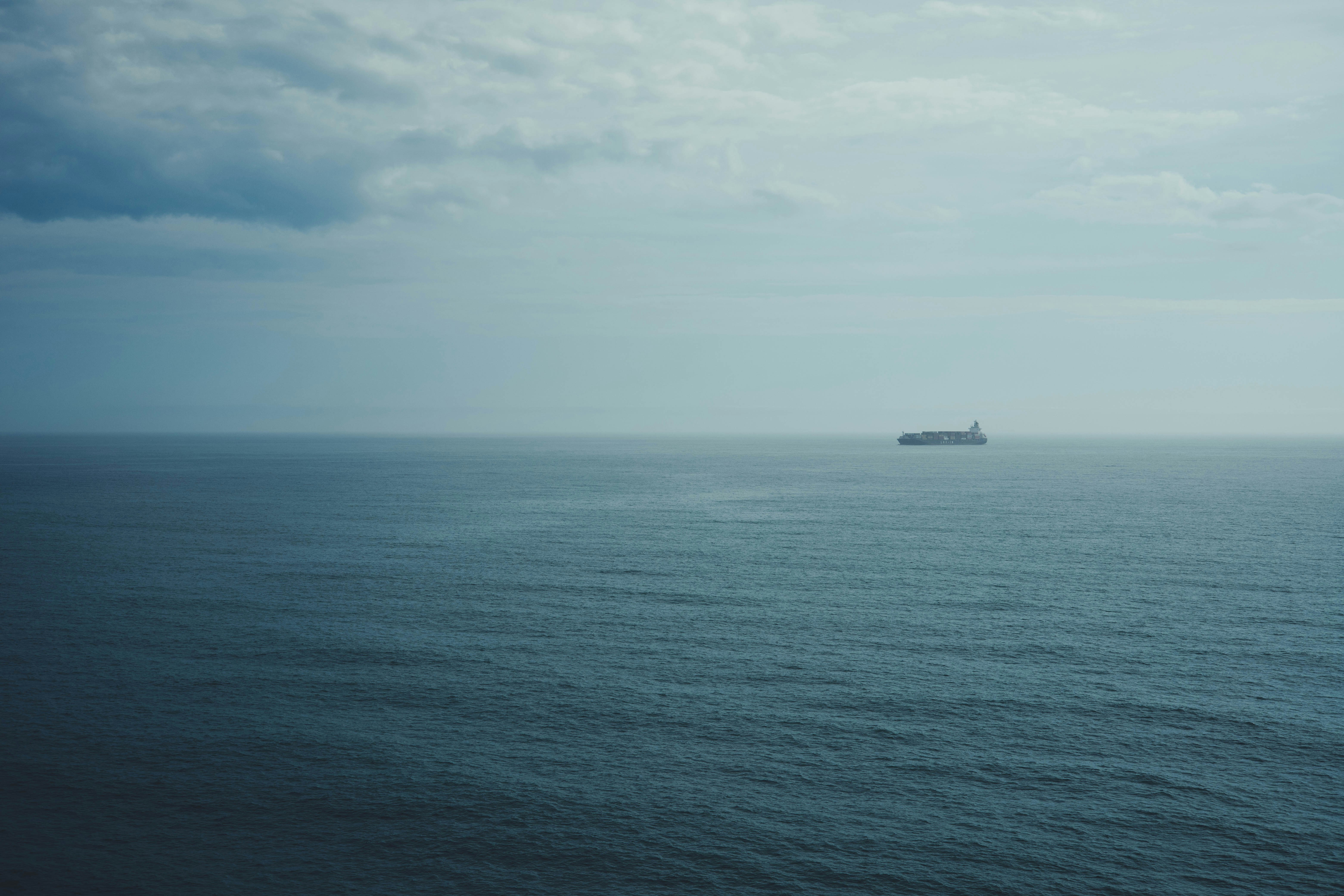 Vast Sea Horizon: A Lone Vessel at Midday Calm