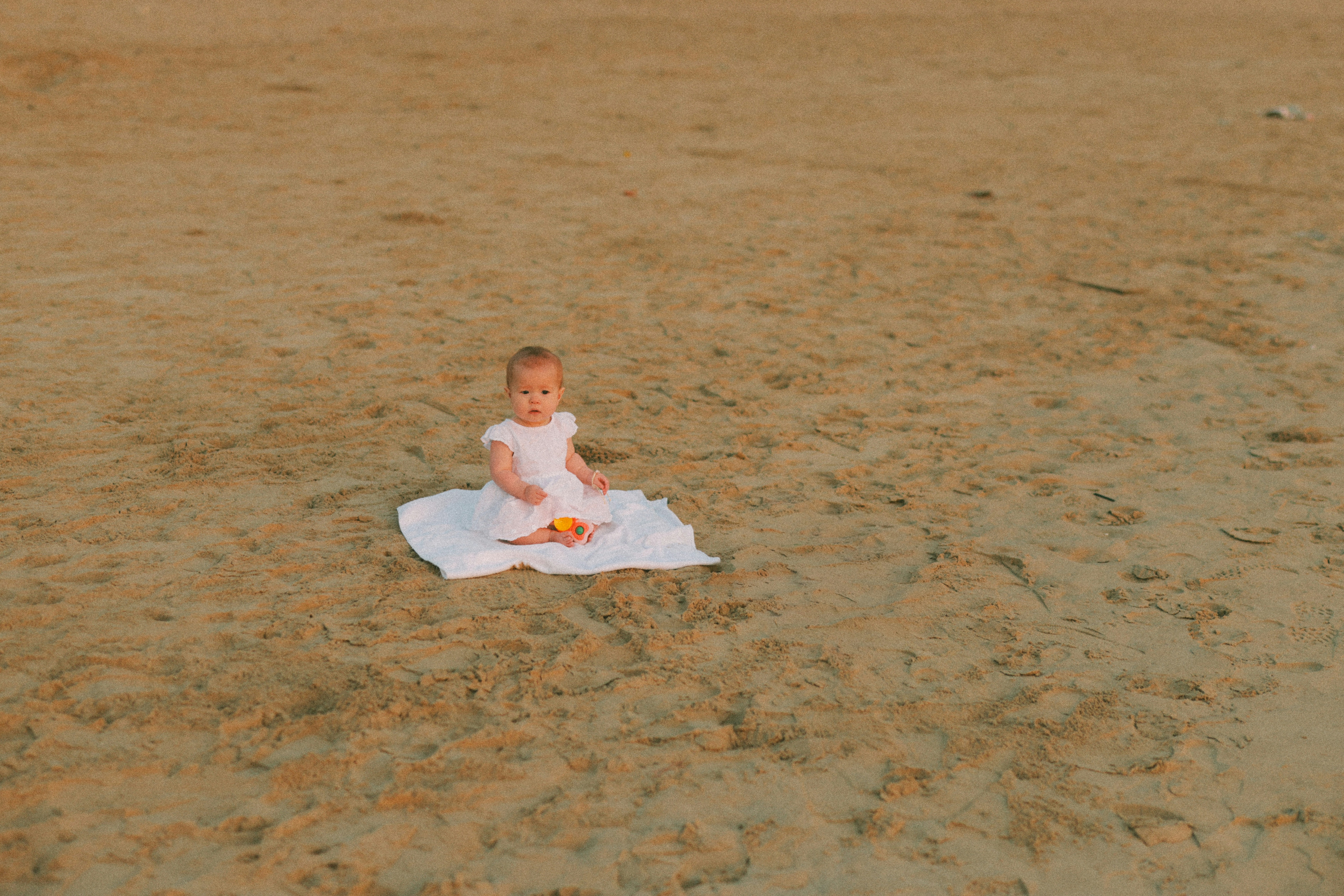 Solitary Moment: A Baby on a White Blanket in a Sandy Expanse