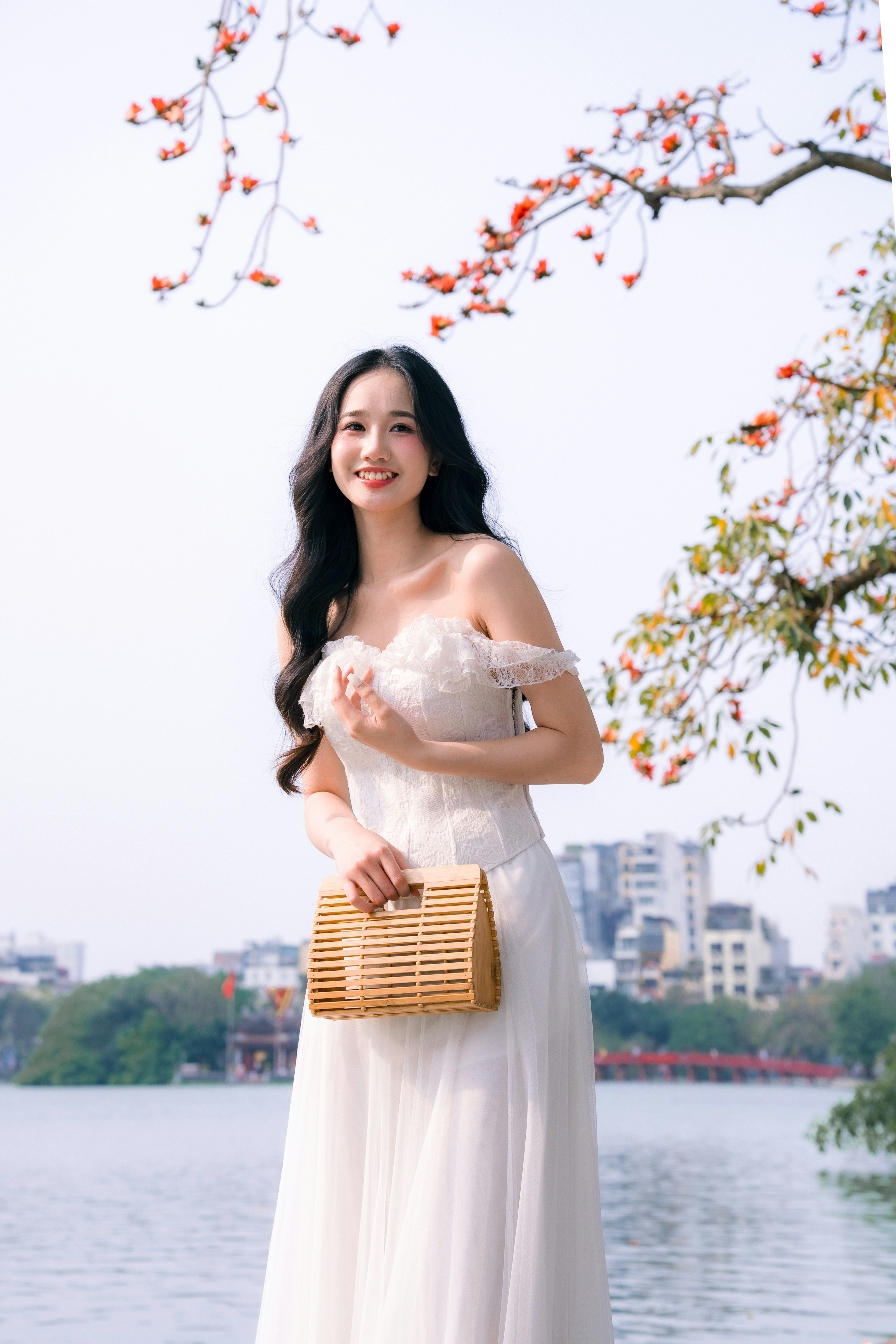 White dress, warm smile: a portrait by the lakeside with blossoming branches