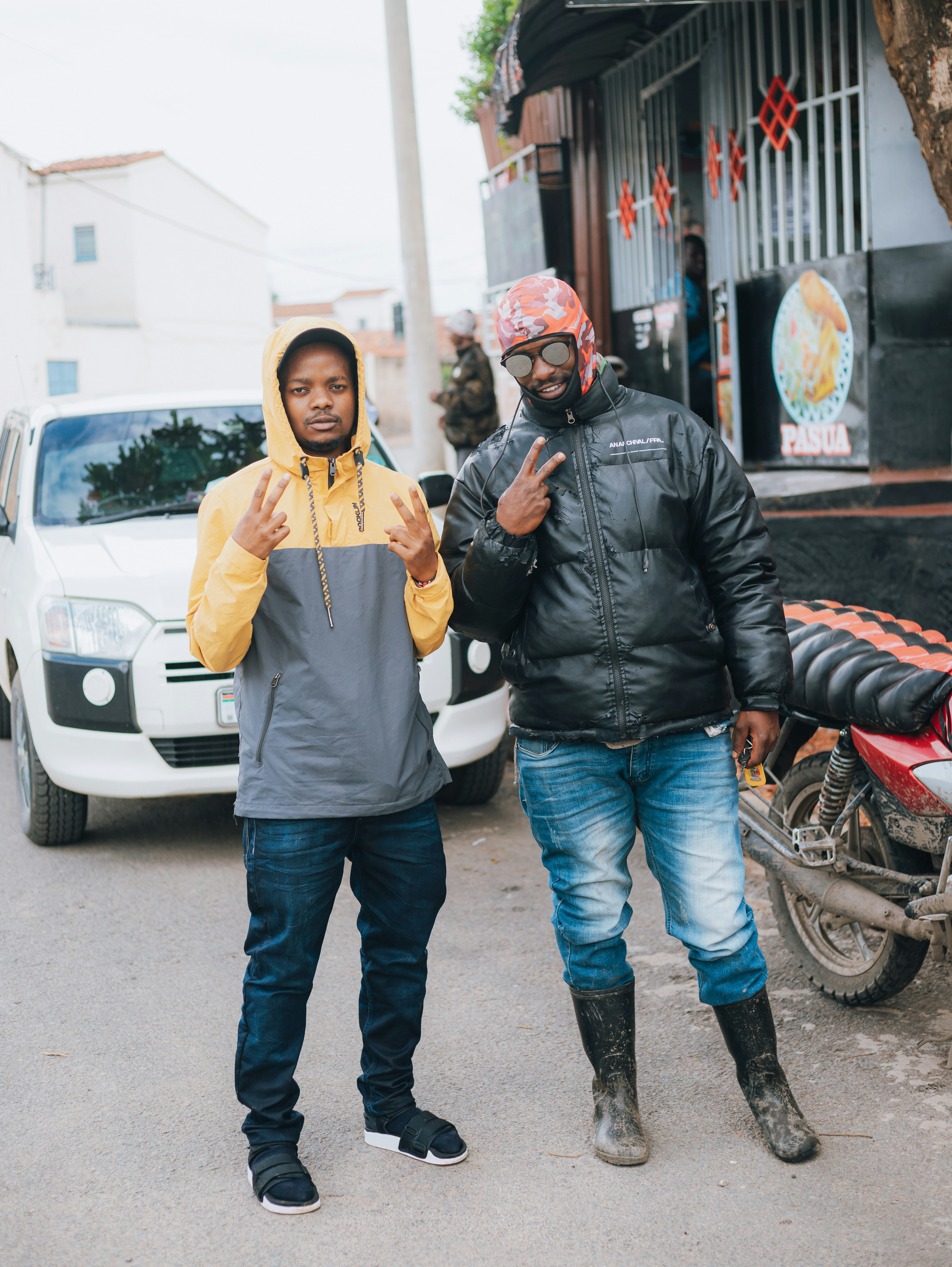 Two friends on a sunlit urban street strike confident poses