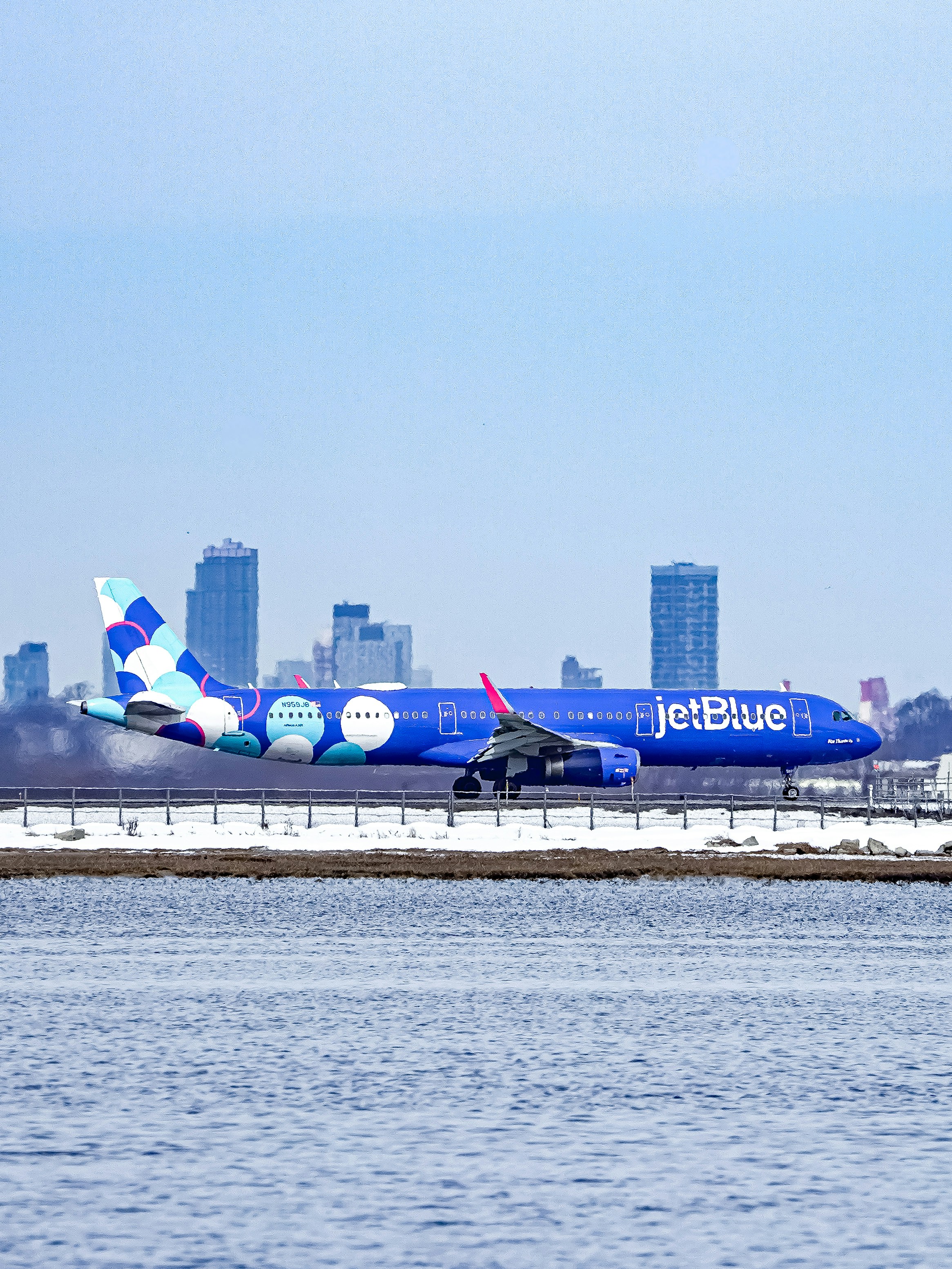 JetBlue A320 on a Snowy Waterfront, City Skyline in the Background