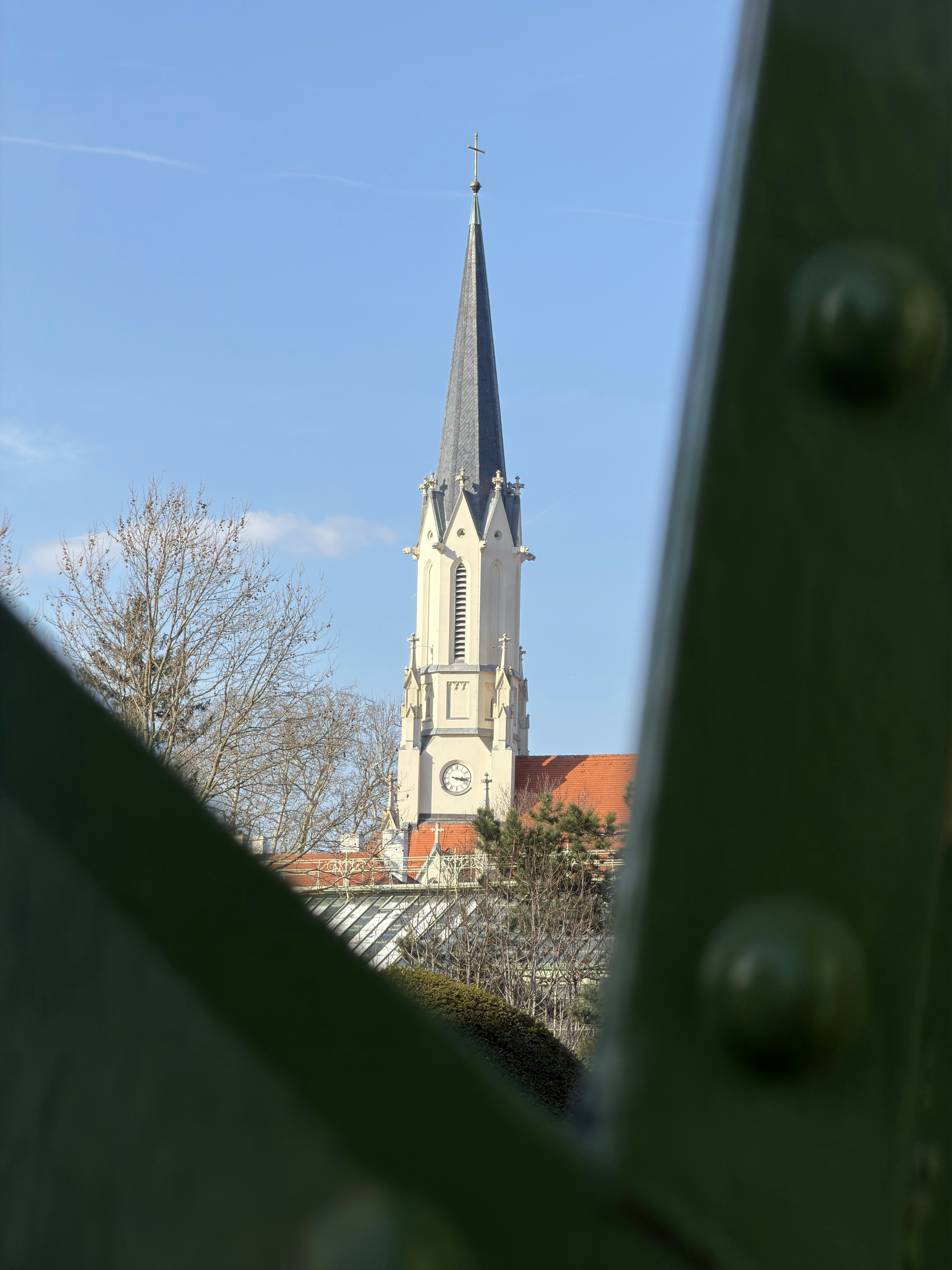 Stately steeple framed by green ironwork