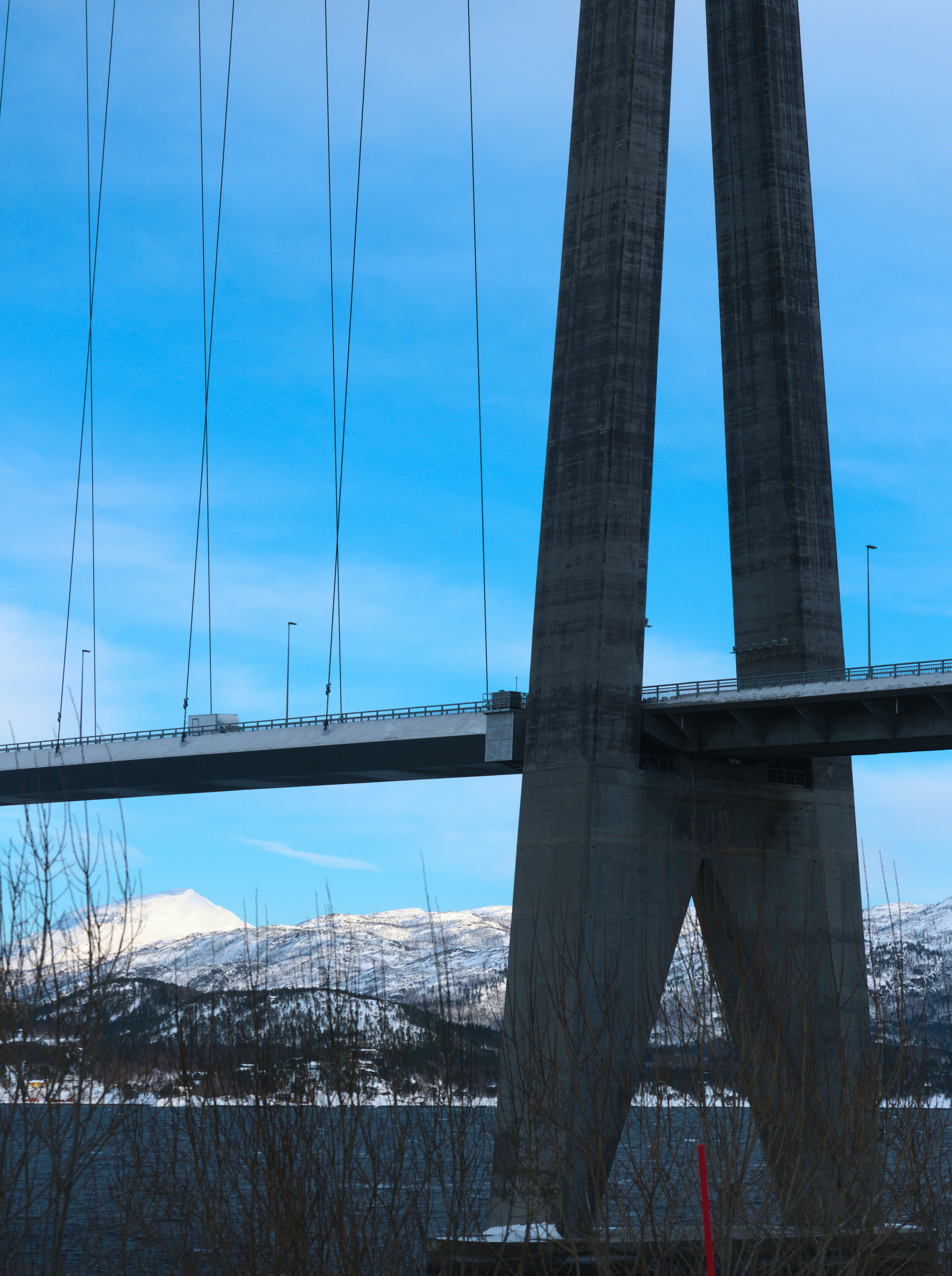Anchored by Steel: A Snowy Bridge Framed Against Alpine Blue