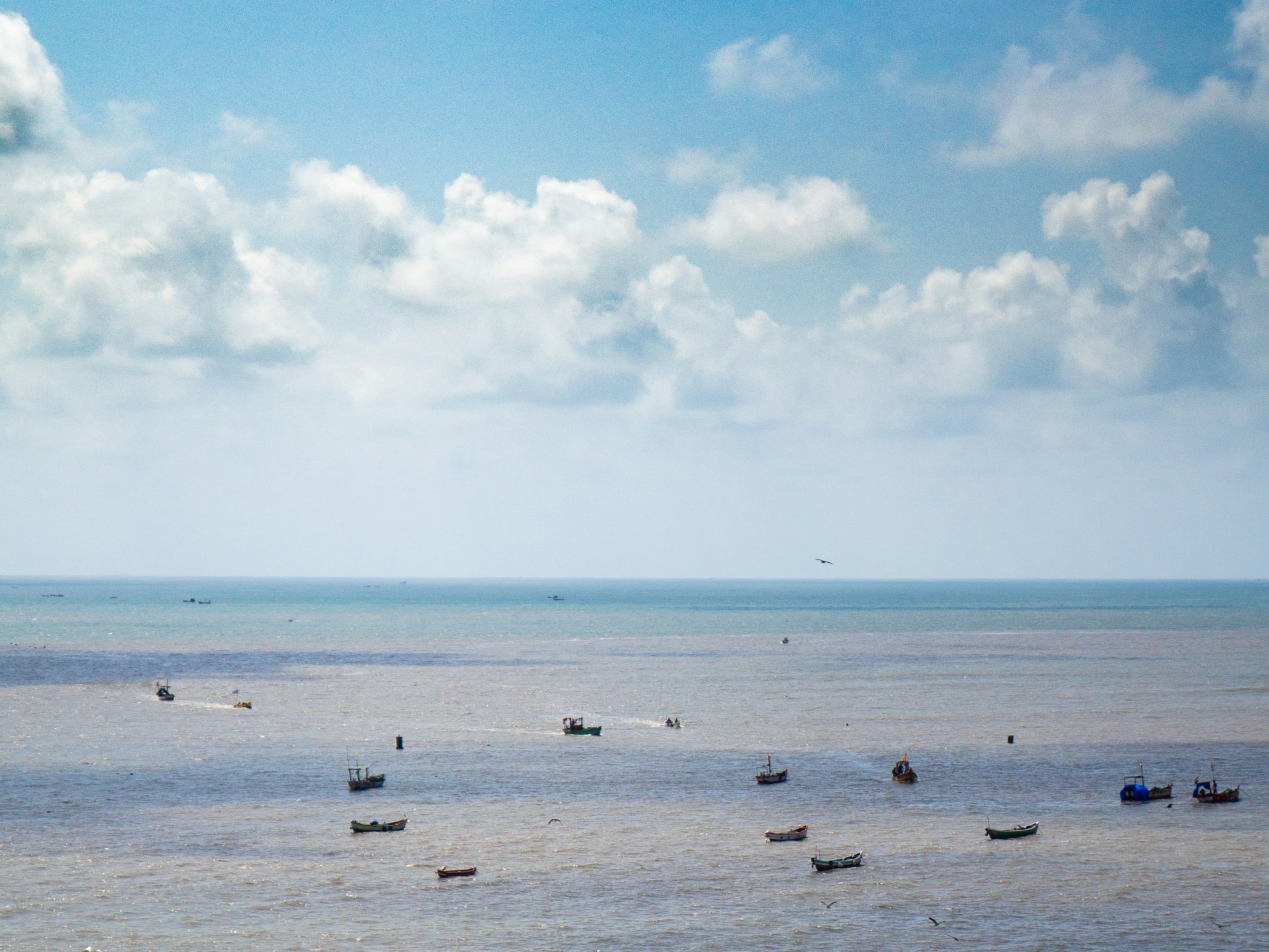 Calm Sea, Distant Fleet: Boats Stretched Across a Cloudlit Horizon