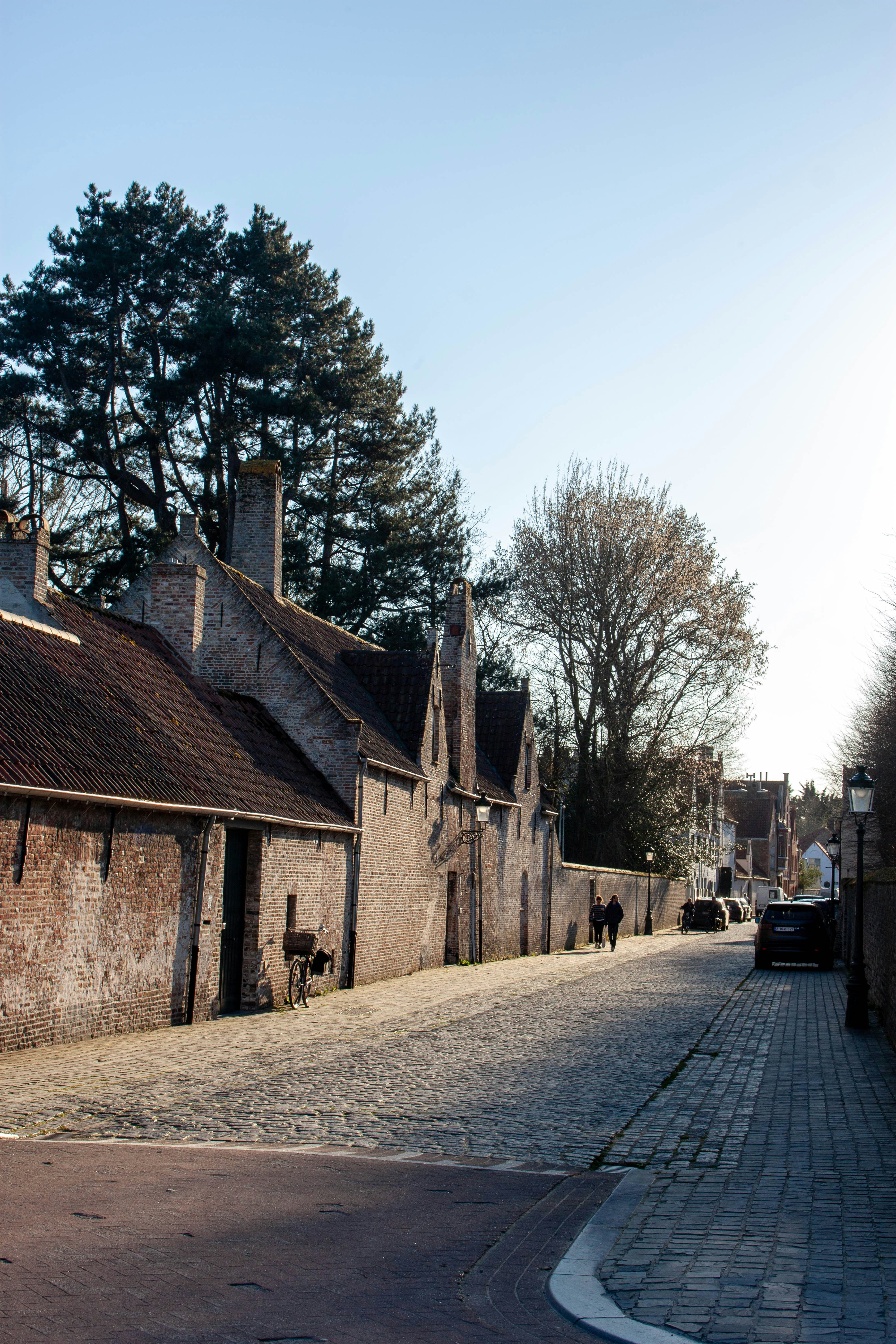 Sunlit Flemish Street: Cobbled Lane Toward a Quiet Horizon
