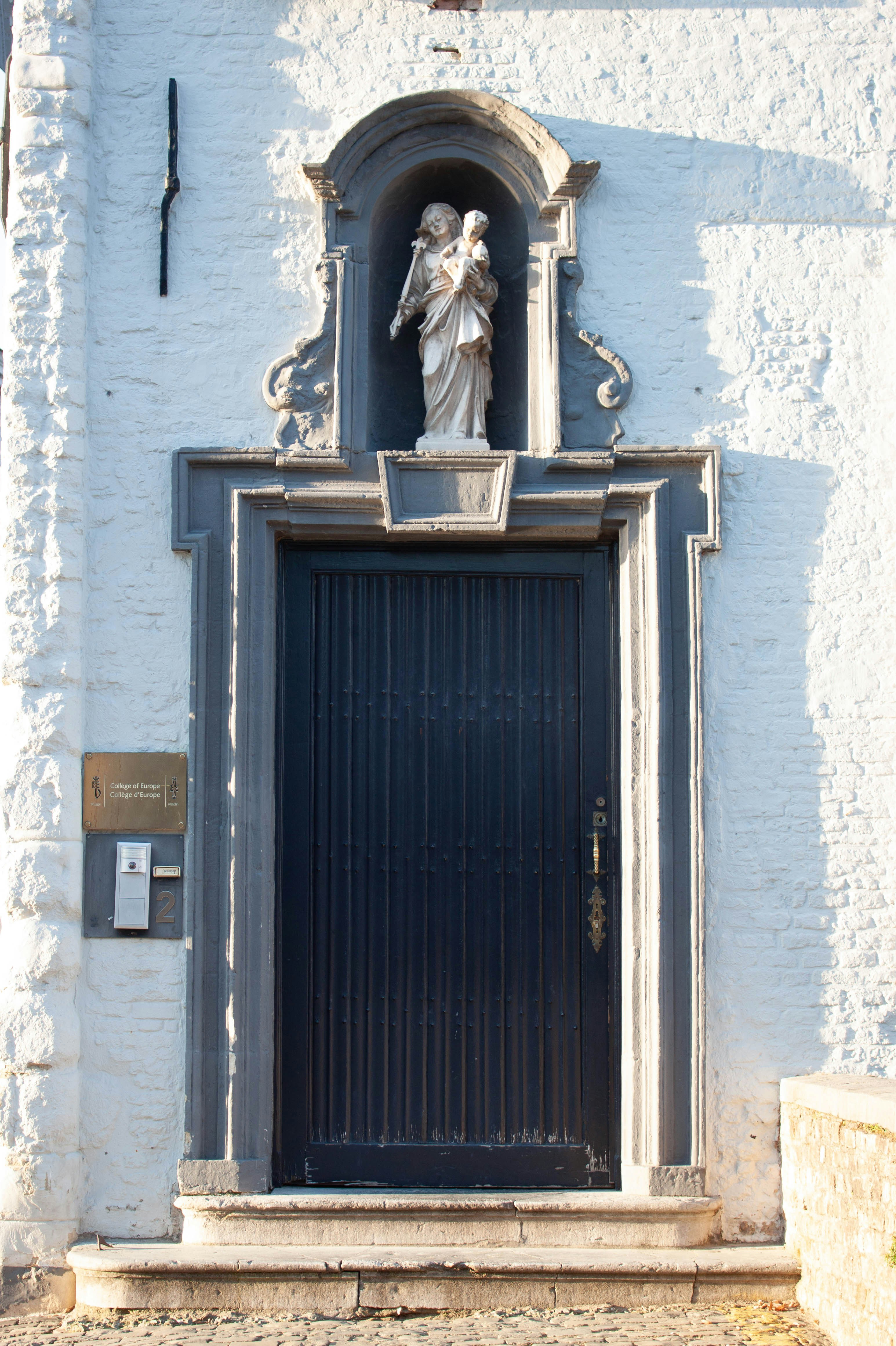 Noble Entry: A carved statue watches over a dark arched doorway