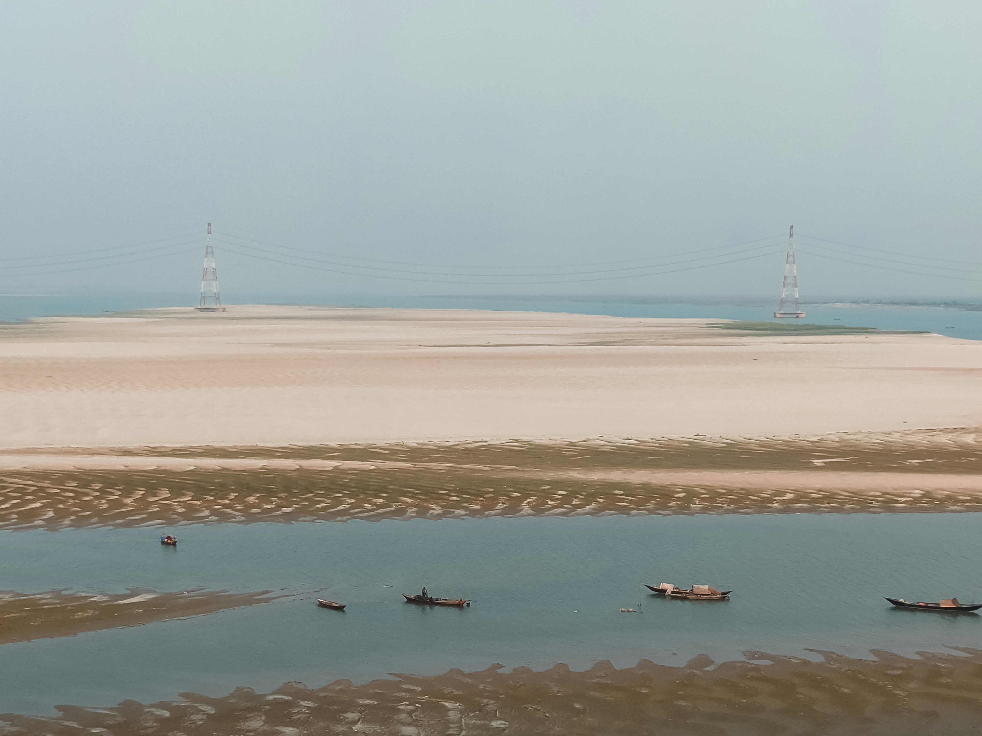 Low Tide, Quiet Barrage: Sand, Water, and Distant Towers