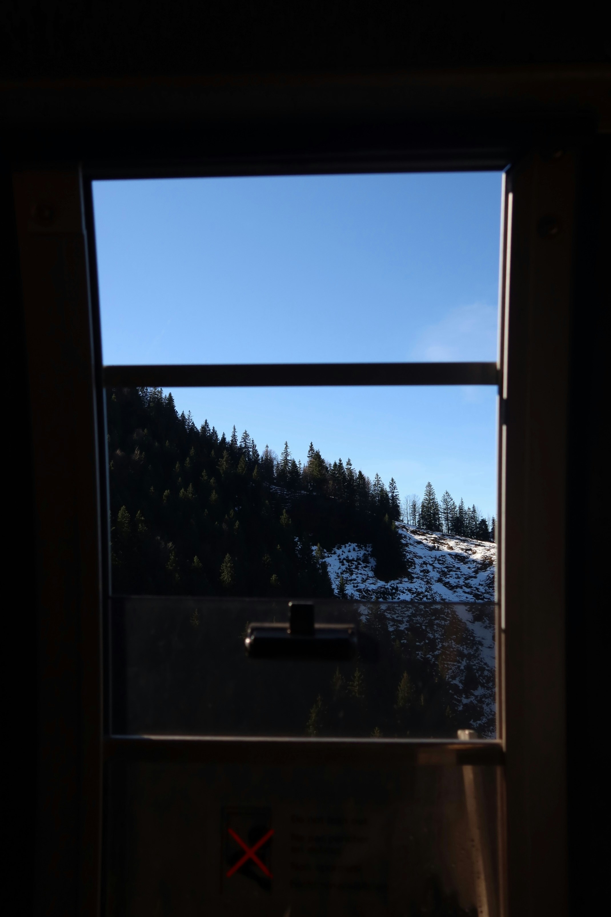 Snowy hillside framed by a dark window